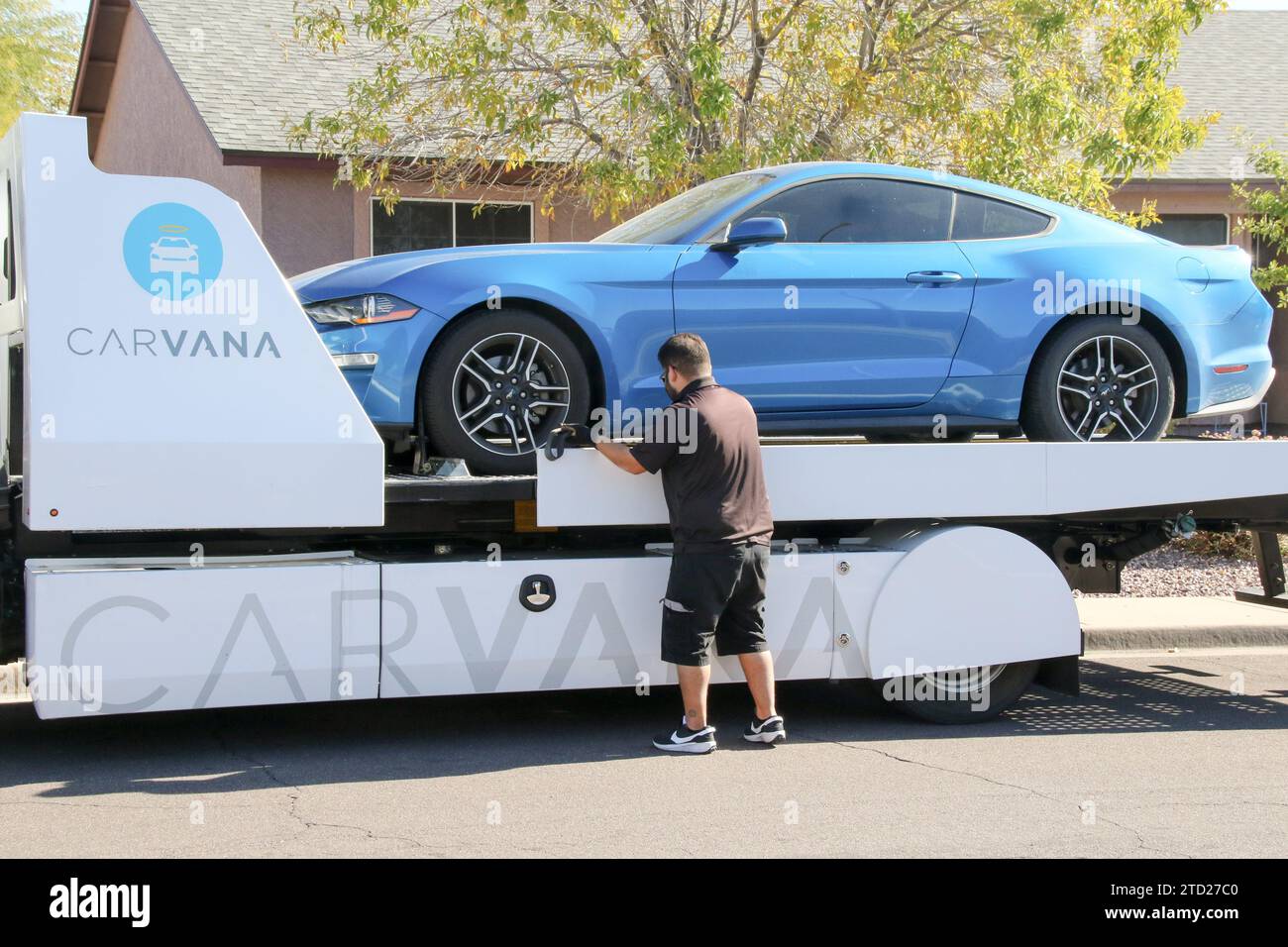 A Carvana representative securely fastens a car sold on-the-spot onto a ...