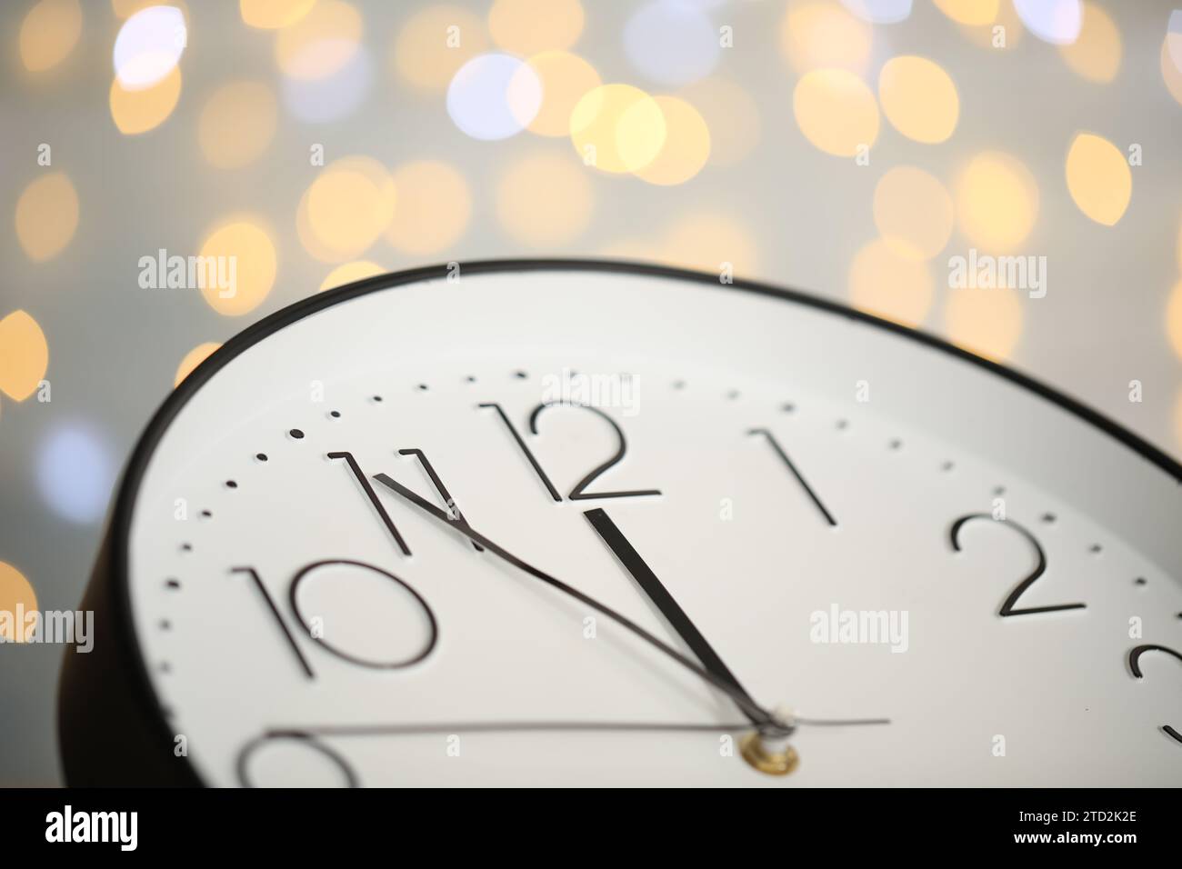 Clock showing five minutes until midnight on blurred background ...