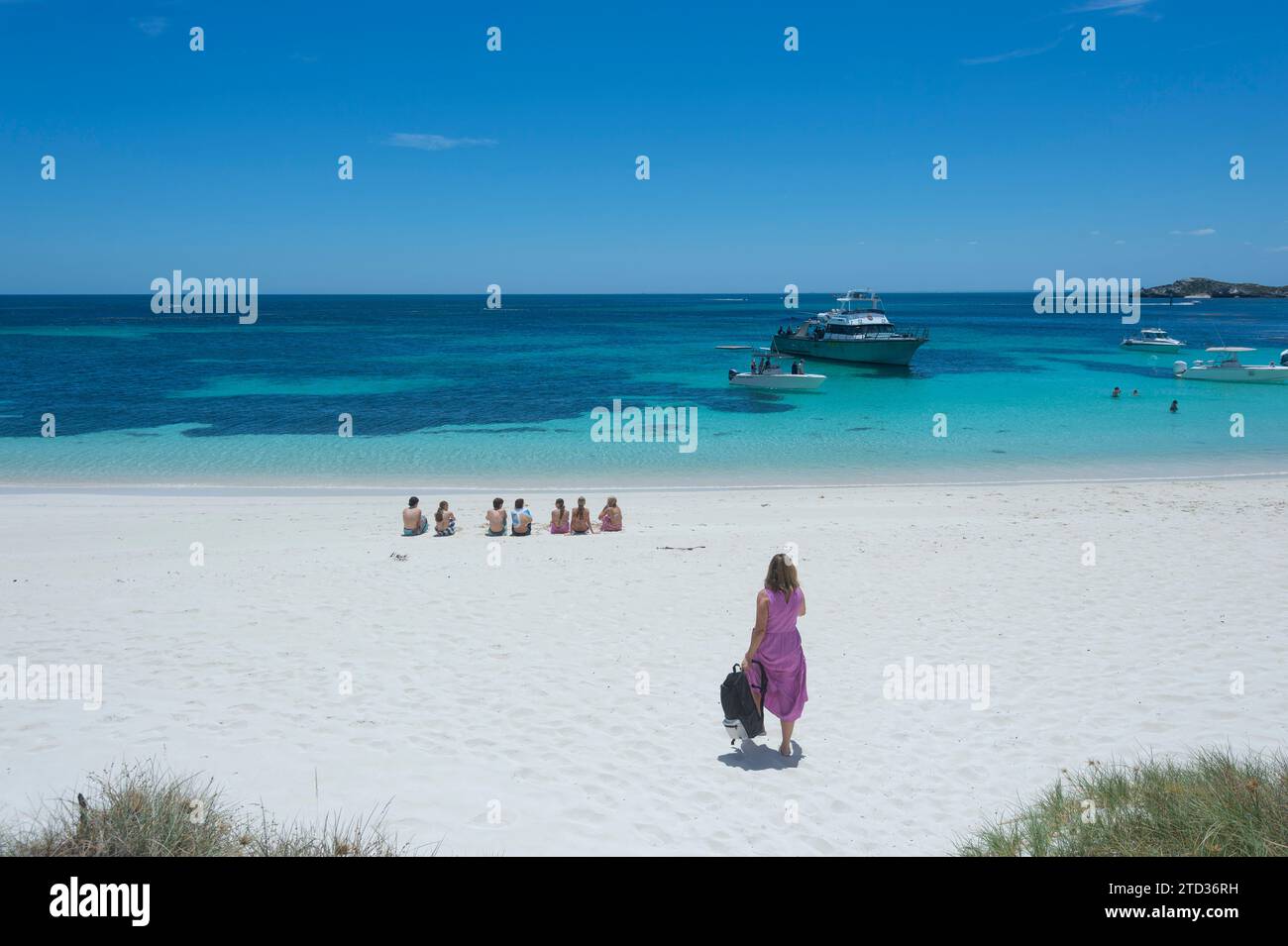 Tourists on an idyllic white sandy beach with turquoise water on ...