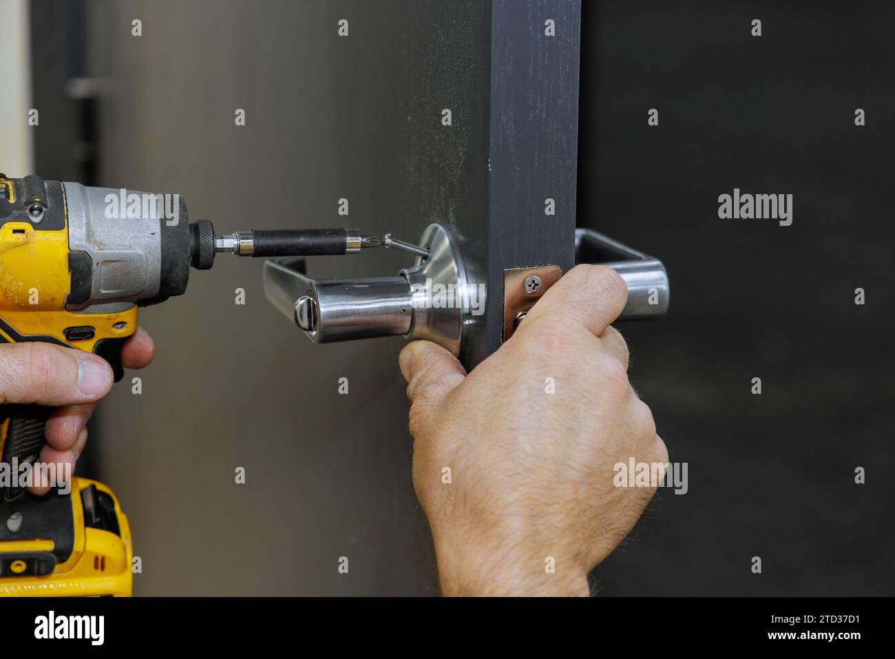 Using screwdriver, carpenter installs lock handles on room door Stock ...