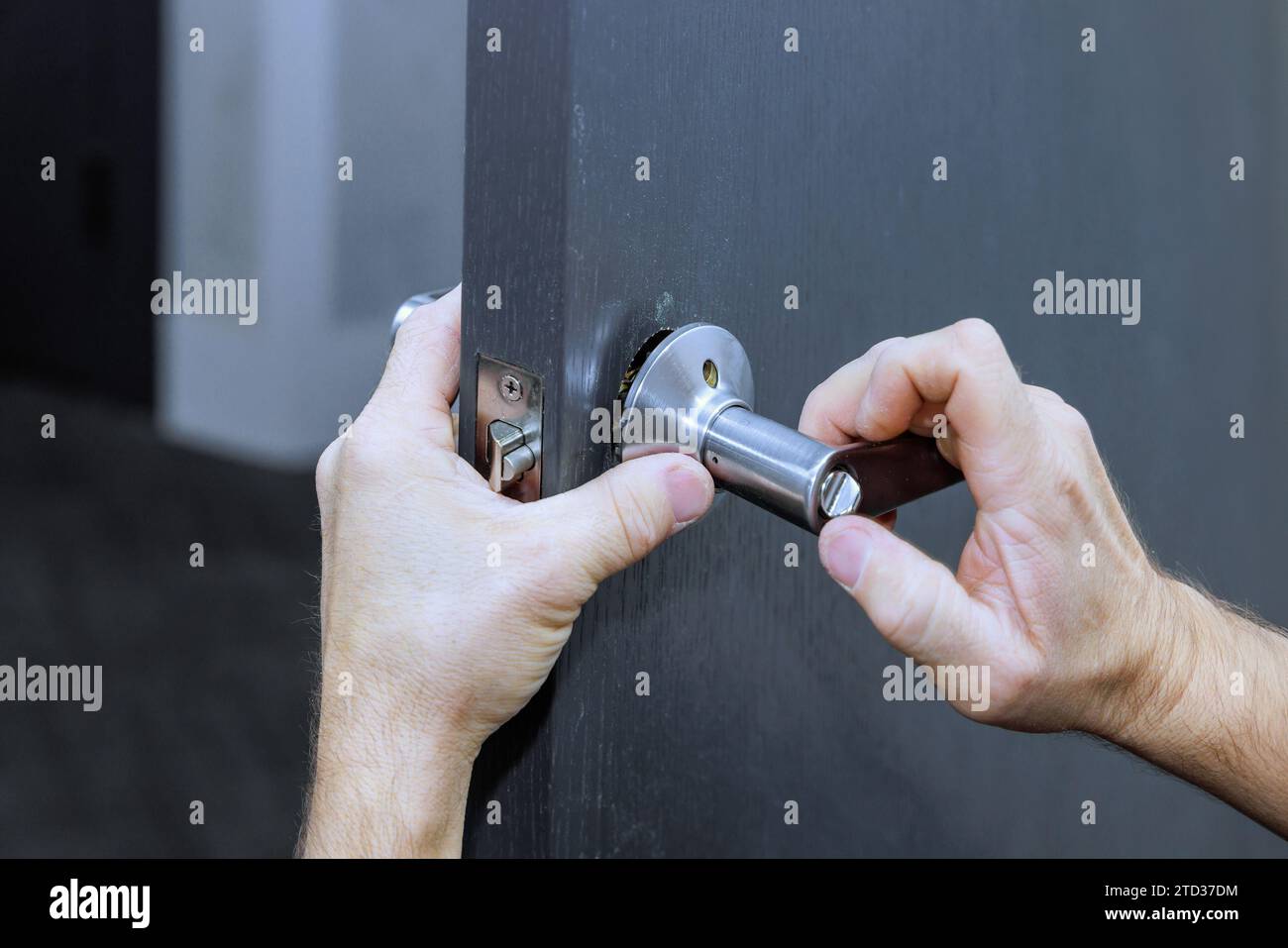 Carpenter installs handle on door of room at new house Stock Photo - Alamy