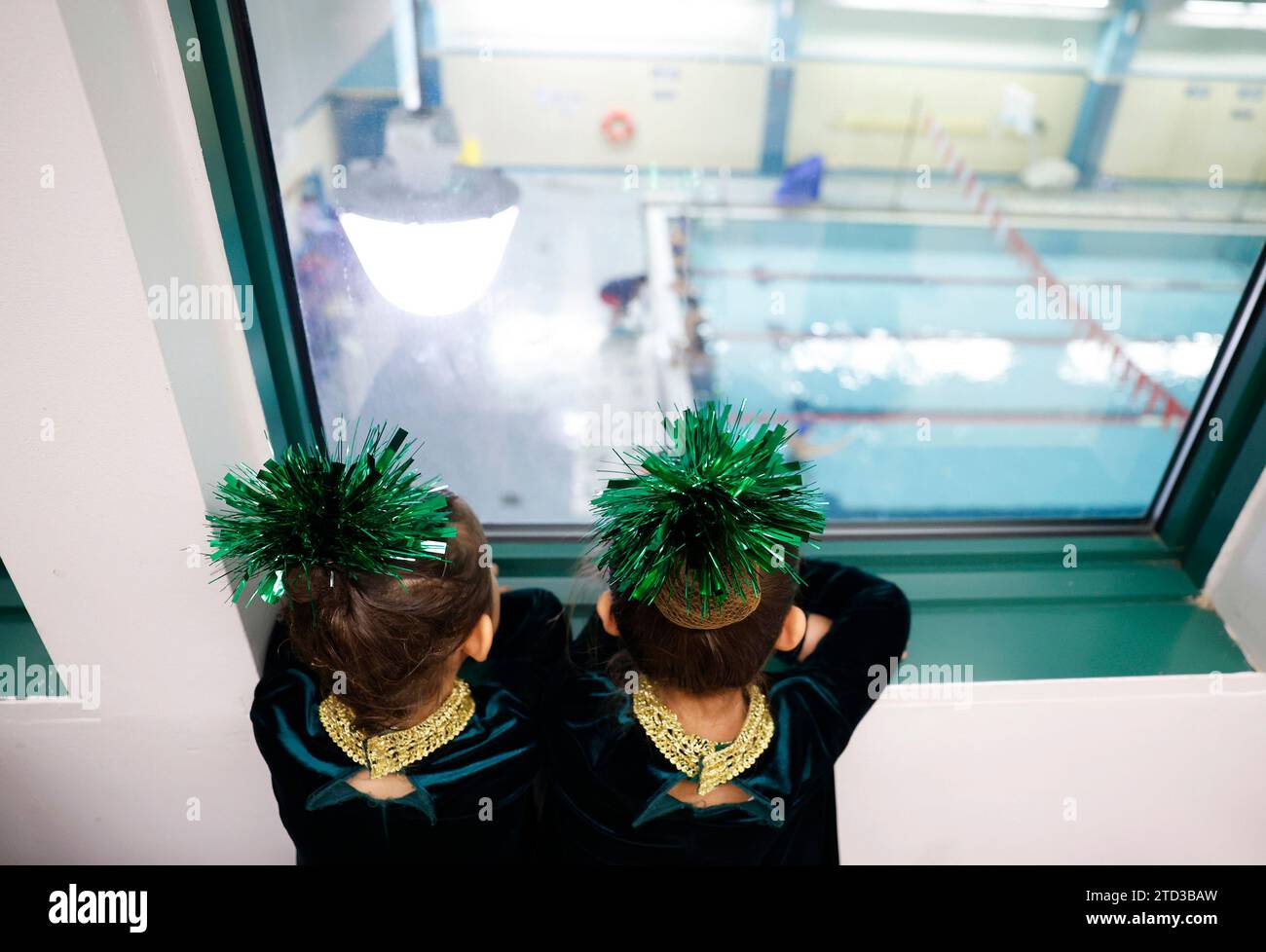 Dancers watch a pool with swimmers through a window as they wait to ...