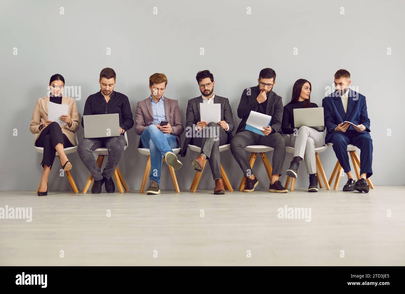Business people sitting by wall while waiting for their turn to ...