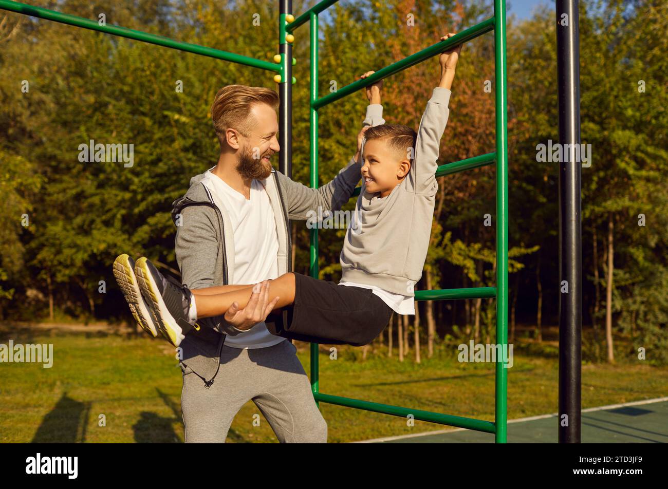 Happy smiling father helping his child boy to do sport fit exercises on ...