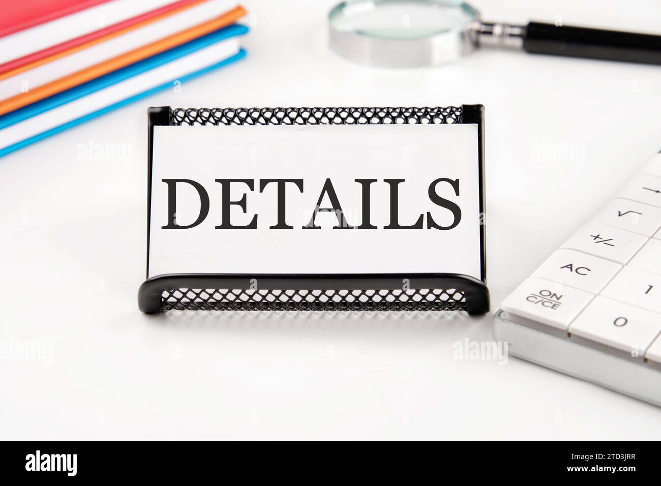 DETAILS text on a business card next to office supplies on a white ...
