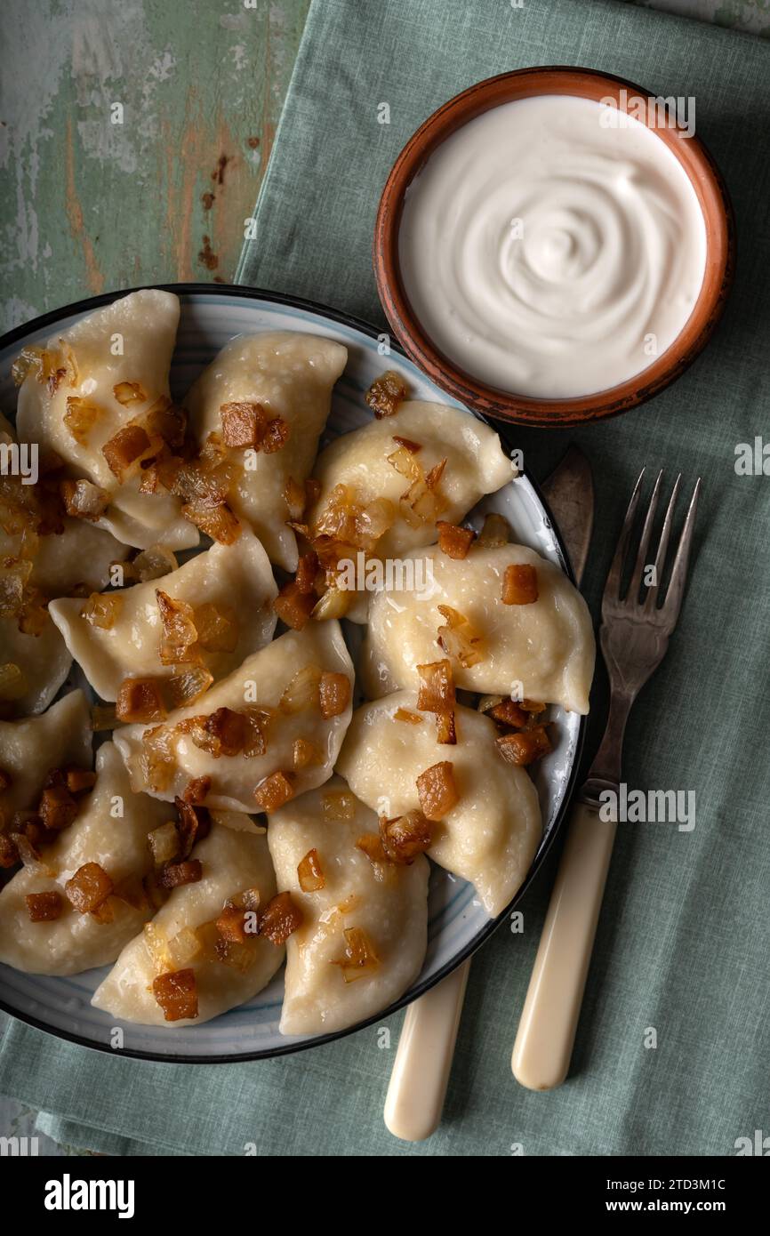 Traditional Ukrainian food - dumplings varenik with sour cream close up. Fried bacon and onion ...