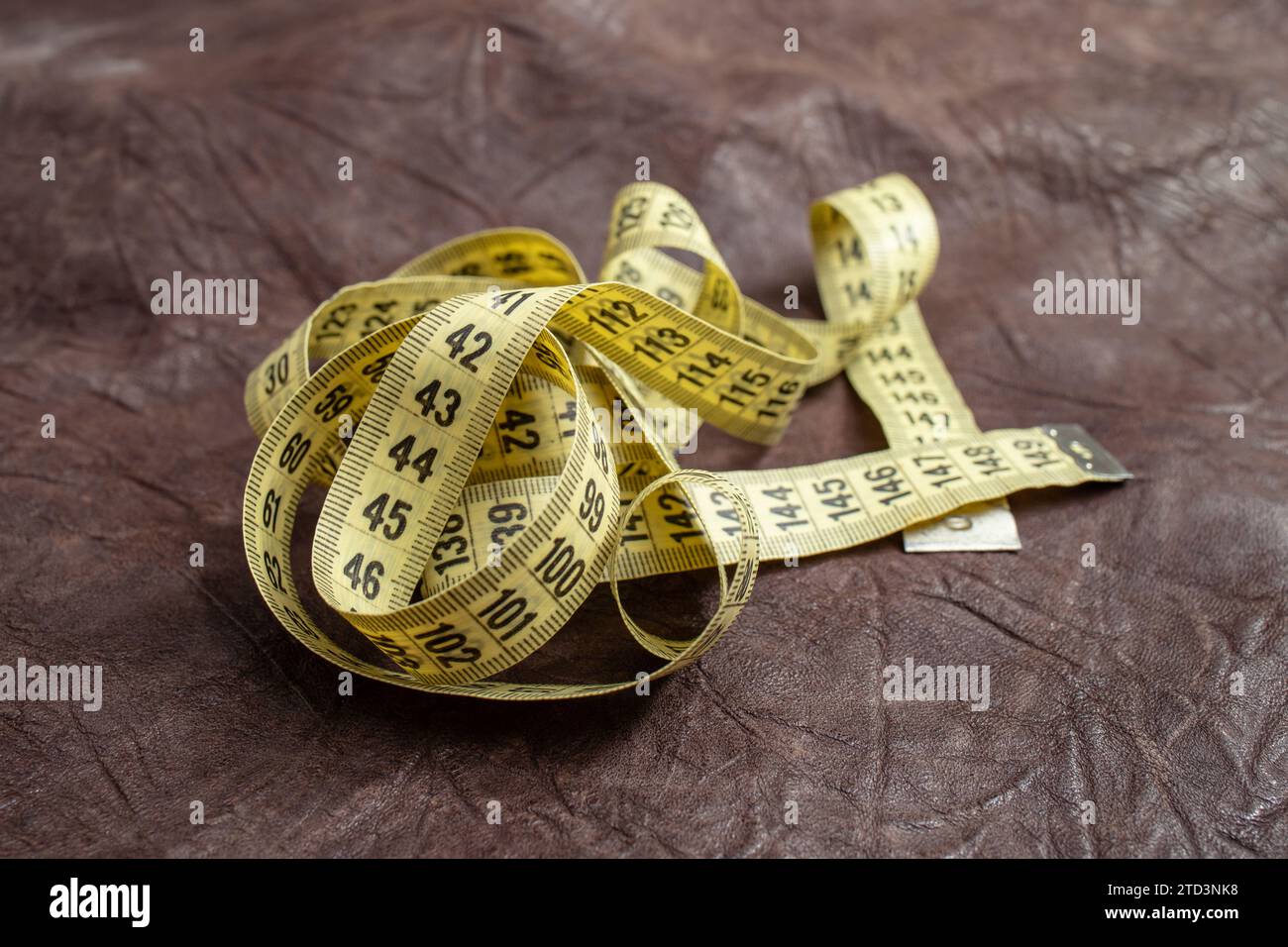 Yellow measuring tape tangled on brown genuine leather texture Stock ...
