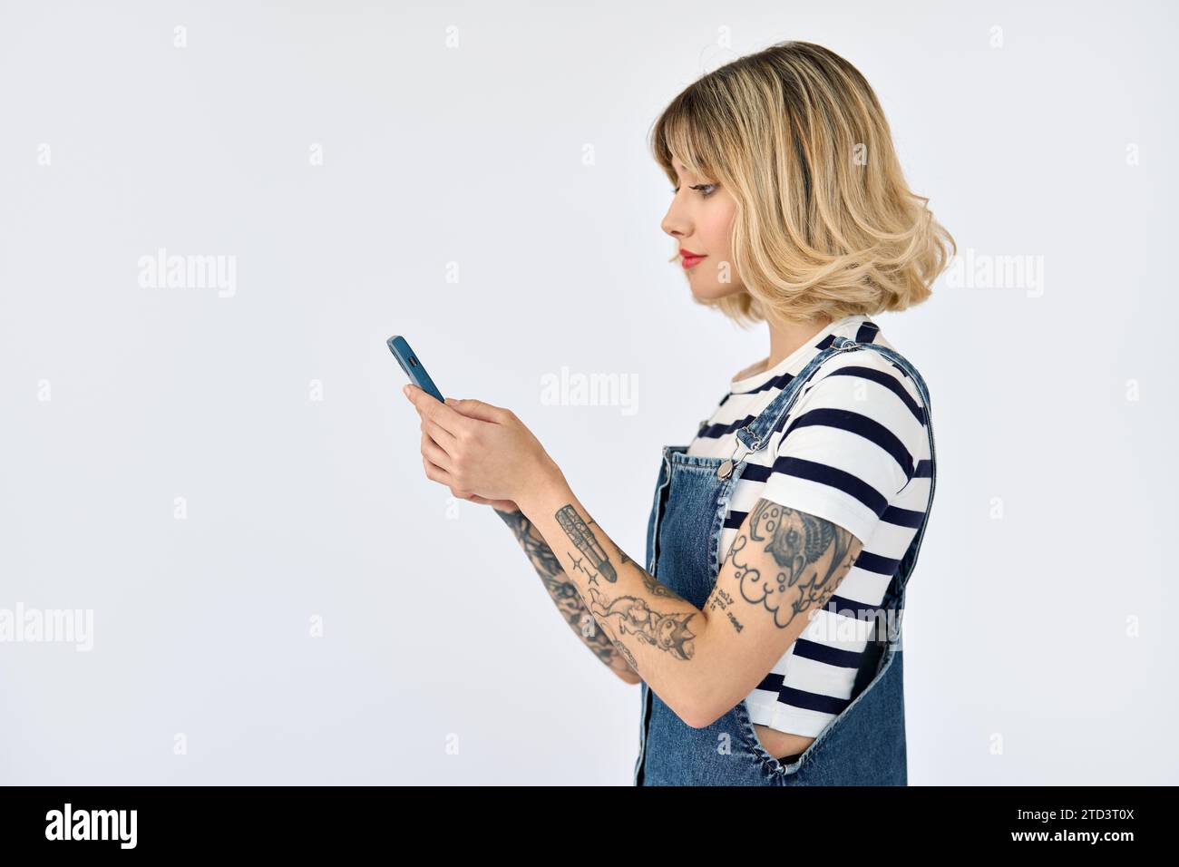 Cool gen z blonde young woman using mobile phone isolated on white ...