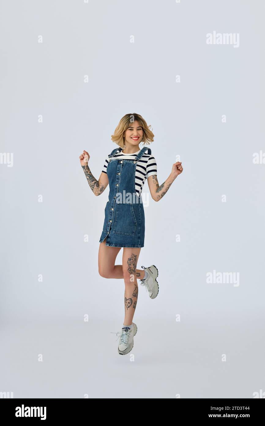 Happy gen z blonde young woman with tattoos jumping isolated on white ...