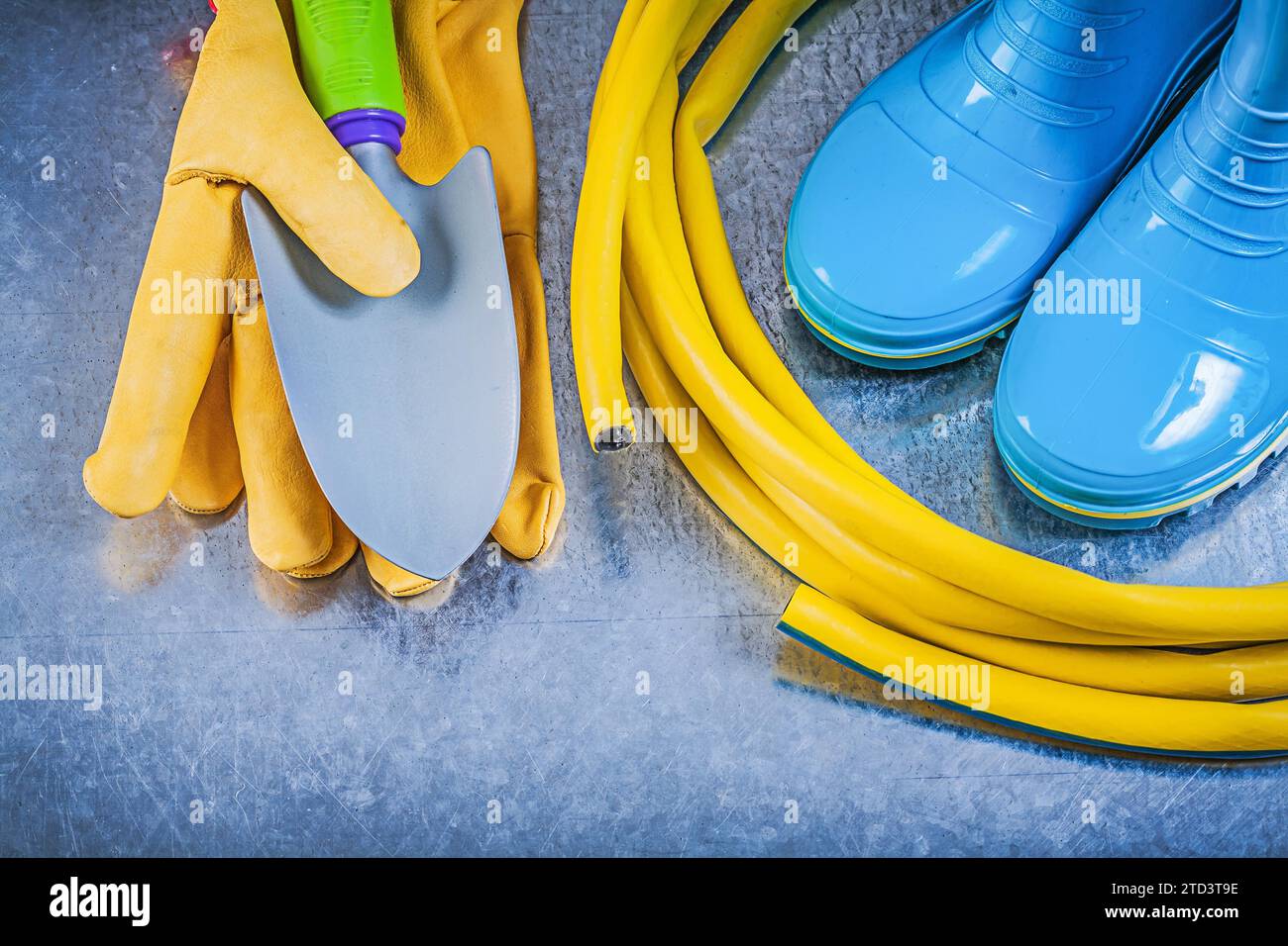 Rubber boots garden hose protective gloves hand spade on metallic ...