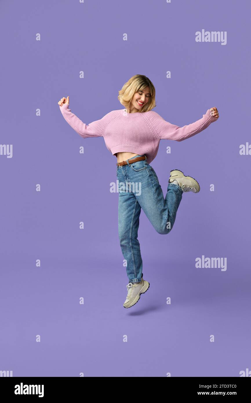 Happy gen z blonde young woman dancing jumping isolated on purple Stock ...