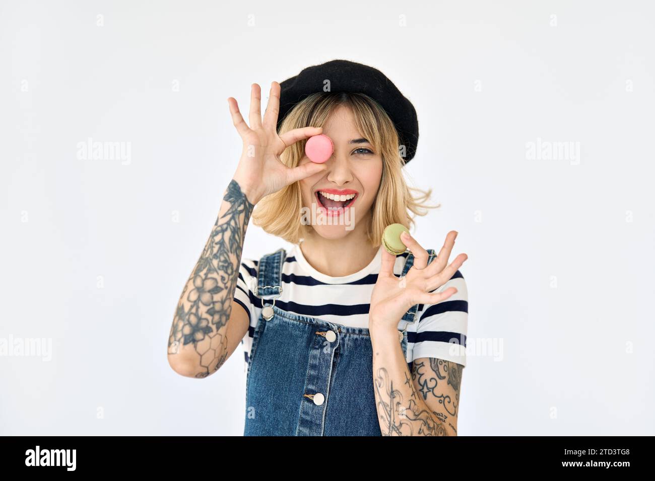 Happy pretty gen z blonde young woman having fun holding macaroons ...