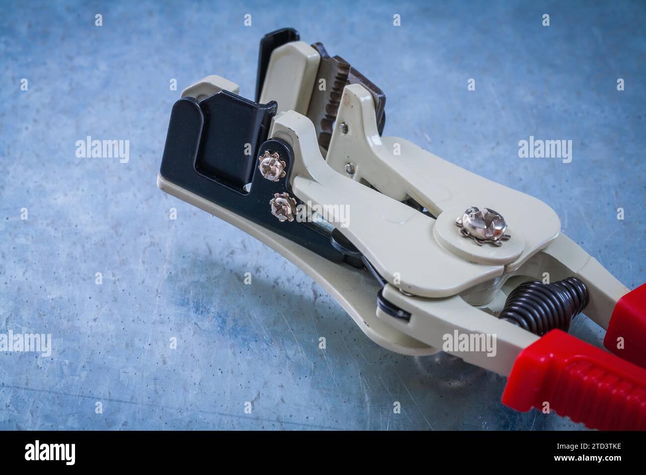 Automatic wire stripper on scratched metallic background in top view ...