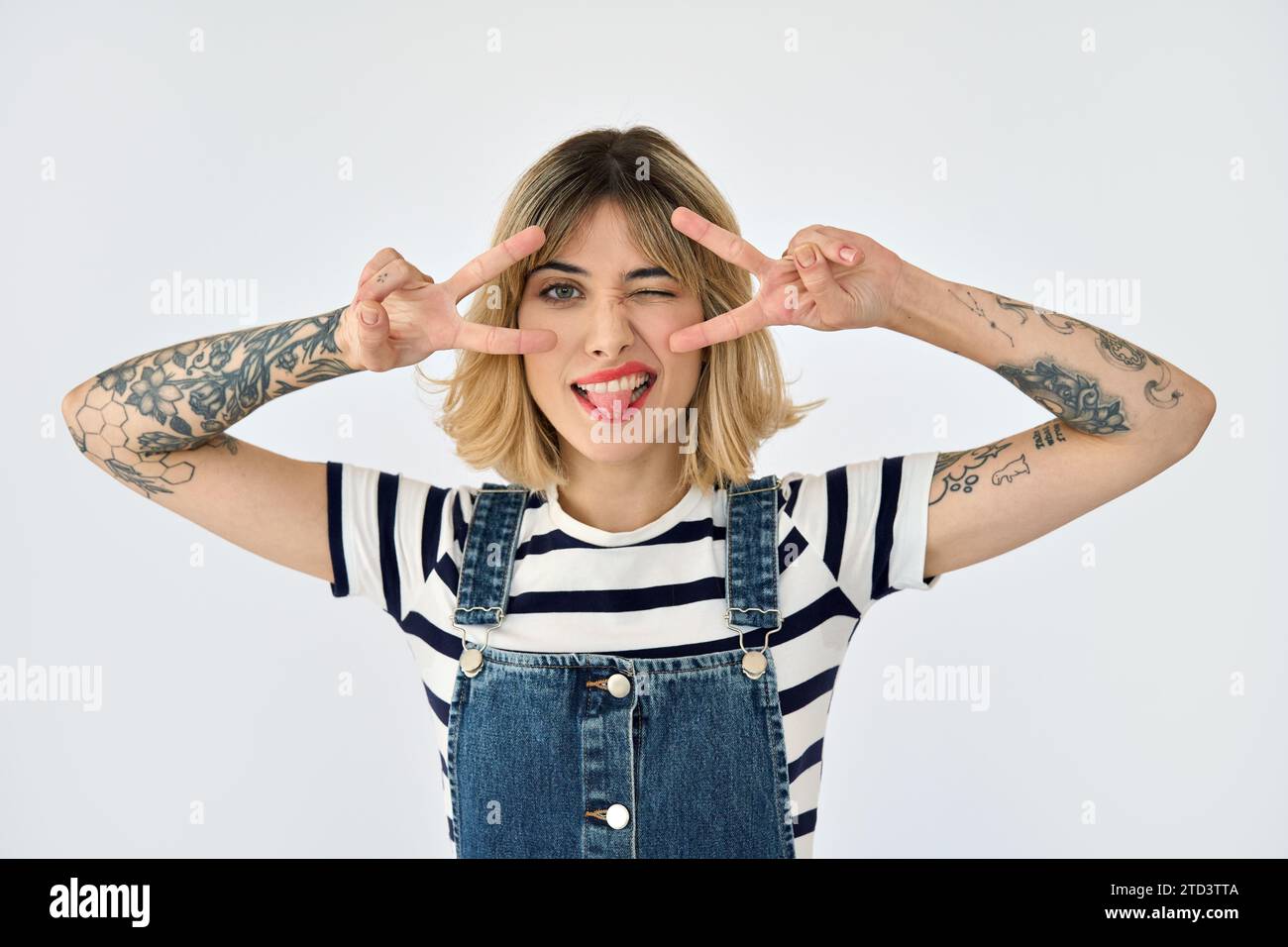 Happy gen z blonde girl showing tongue peace signs isolated on white ...