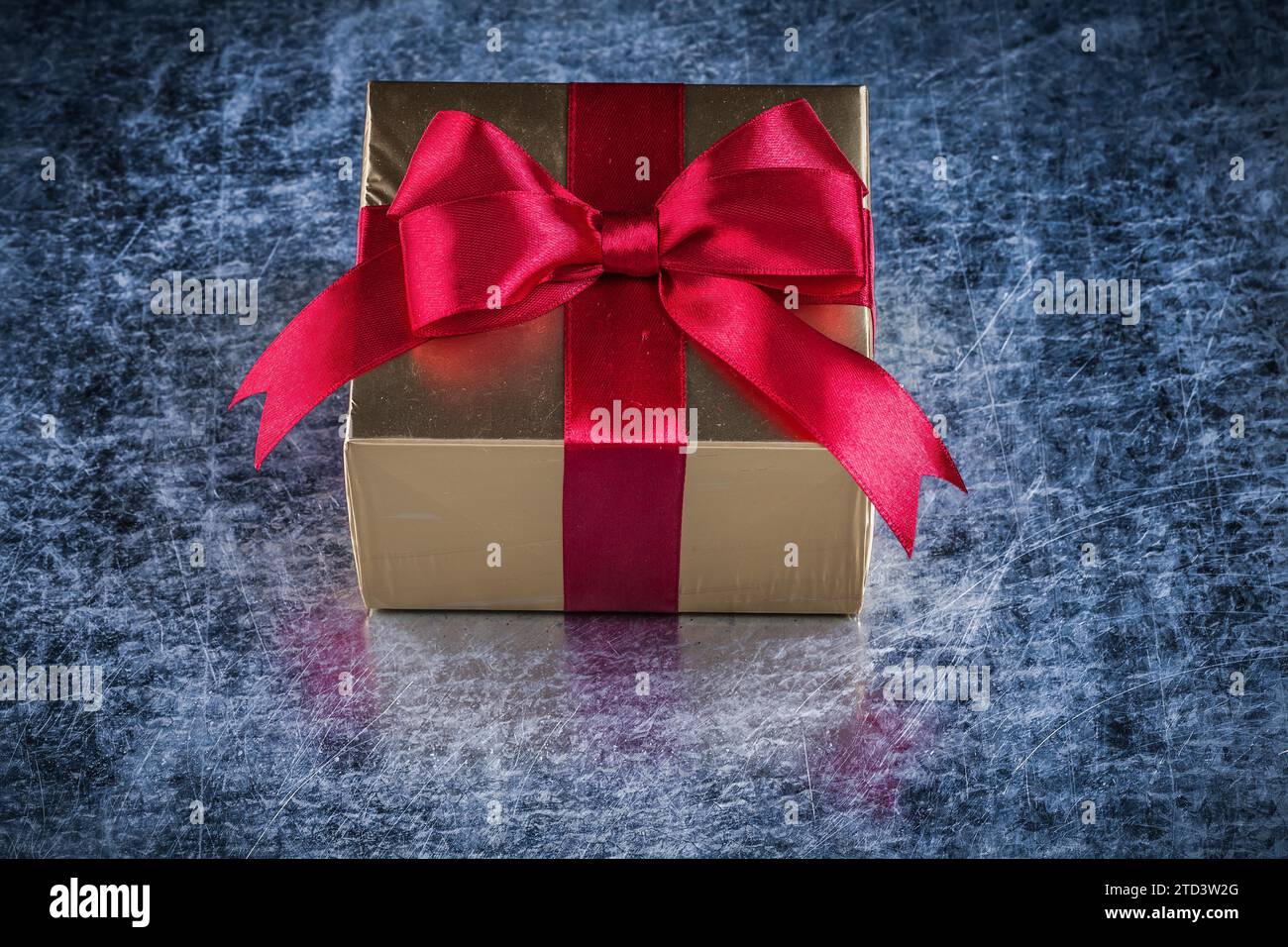 Gift boxes wrapped in shiny gold paper on a scratched metal background ...