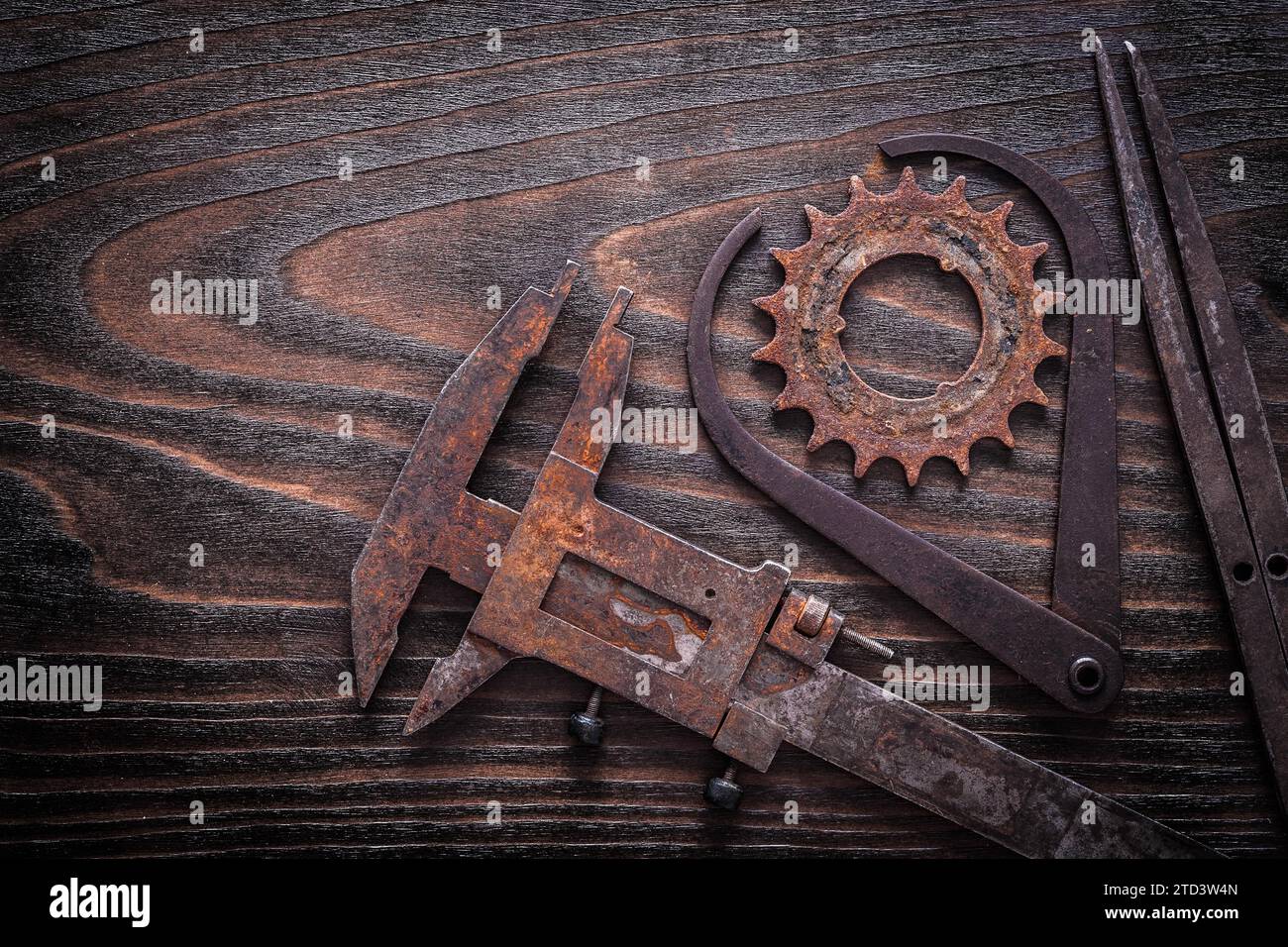 Horizontal version of a rusty caliper with gear wheel on a dark wooden ...