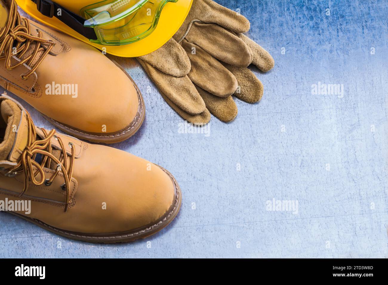 Pair of safety lace boots leather gloves hard hat and safety goggles on ...