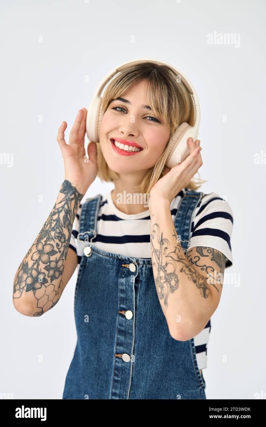 Happy gen z girl with tattoos in headphones listening music isolated on ...