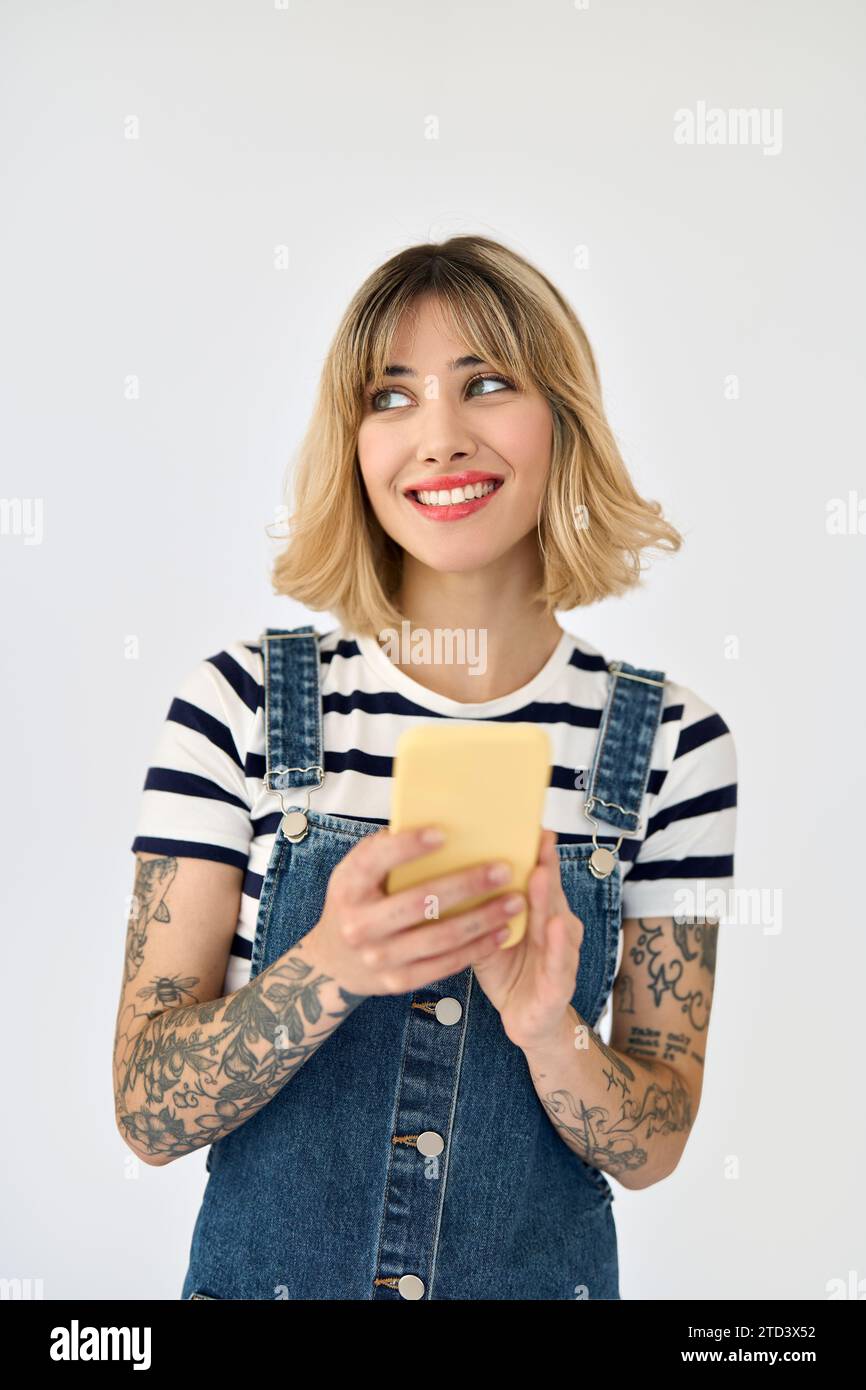 Happy gen z blonde girl using mobile phone looking aside isolated on ...