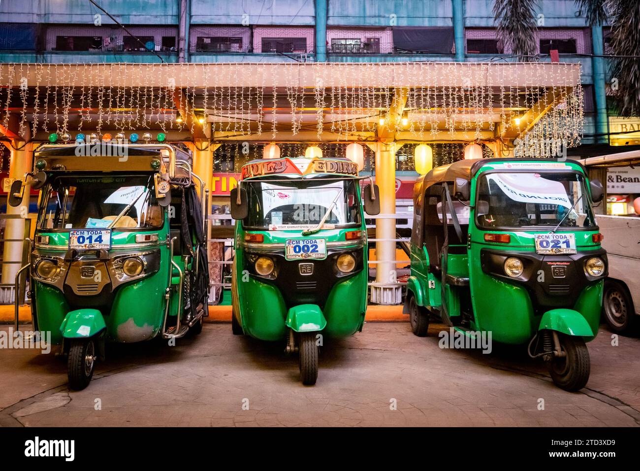 Three stylish green Tuk Tuks lined up outside a shopping centre in the ...