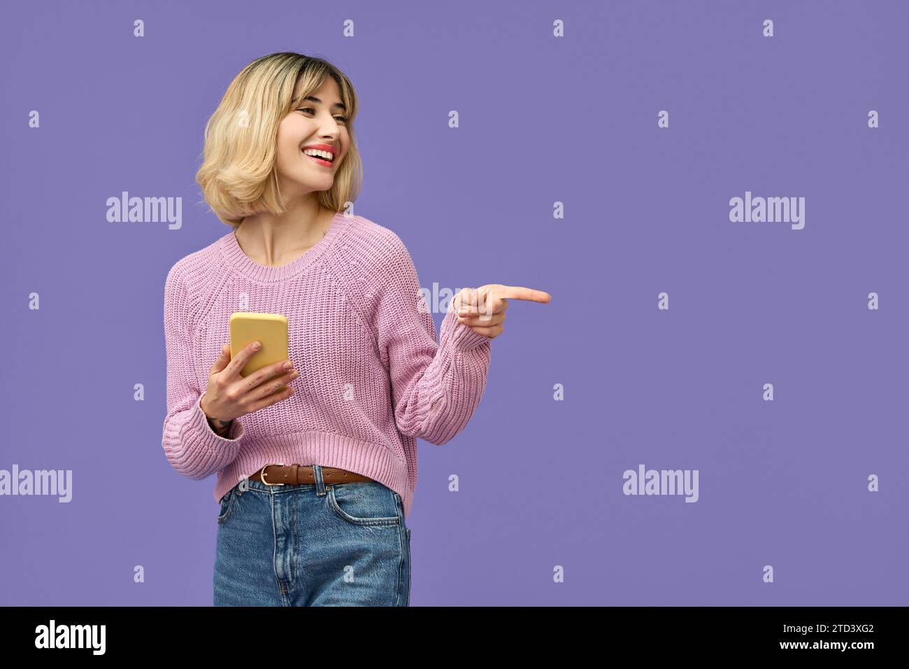 Happy pretty gen z blonde girl holding smartphone pointing at copy ...
