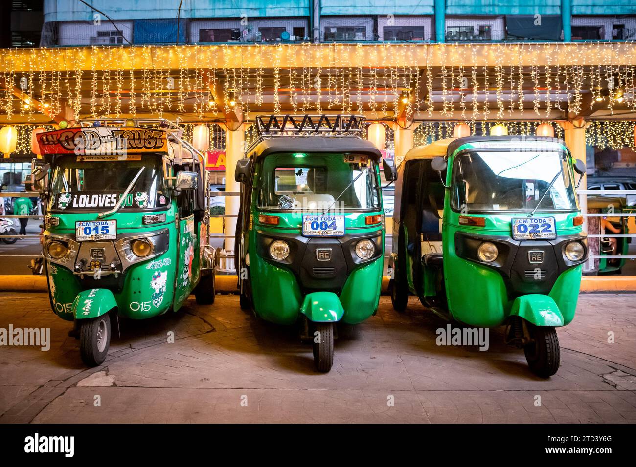 Three stylish green Tuk Tuks lined up outside a shopping centre in the ...