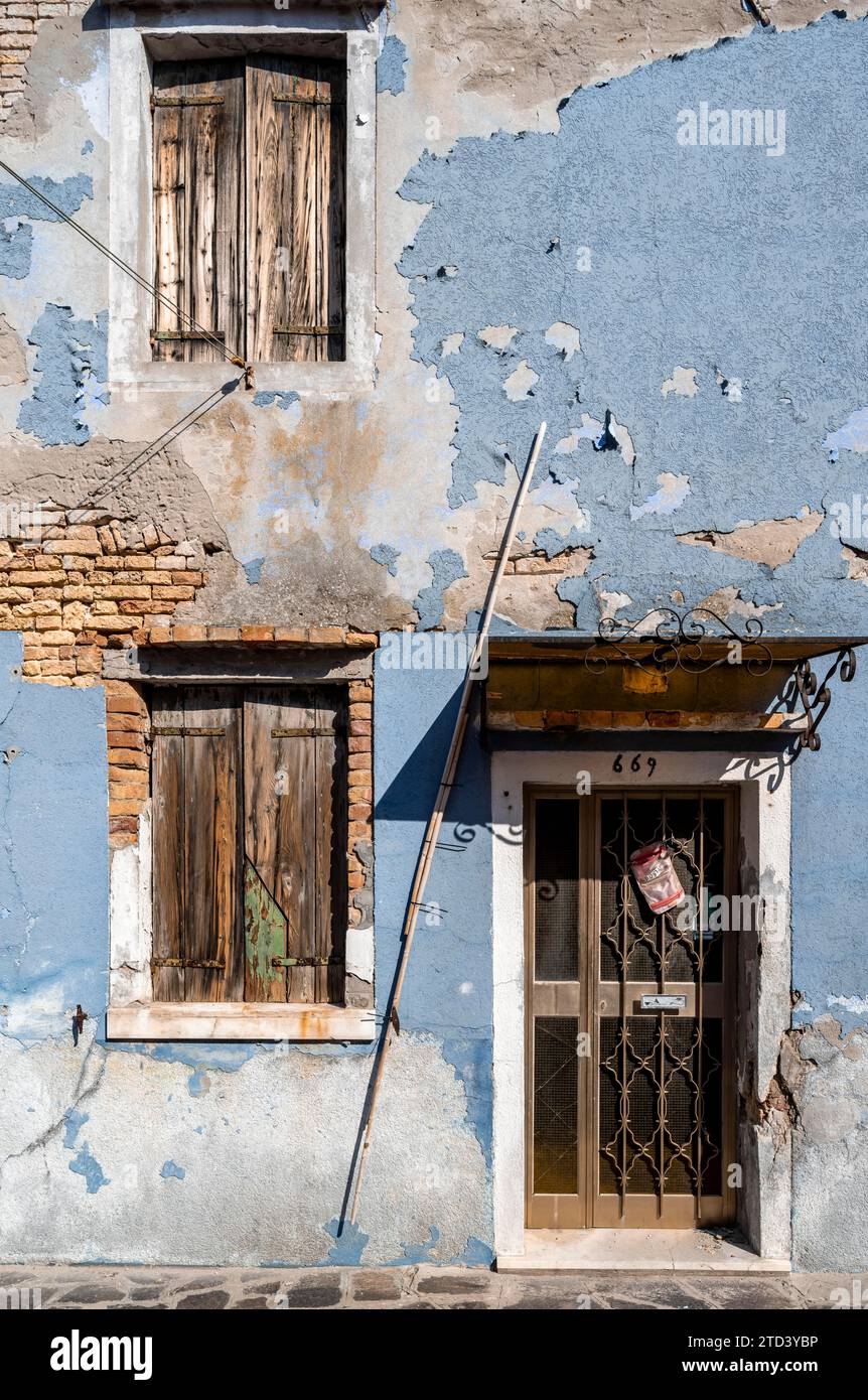 Dilapidated blue house facade with entrance door and windows, colourful ...