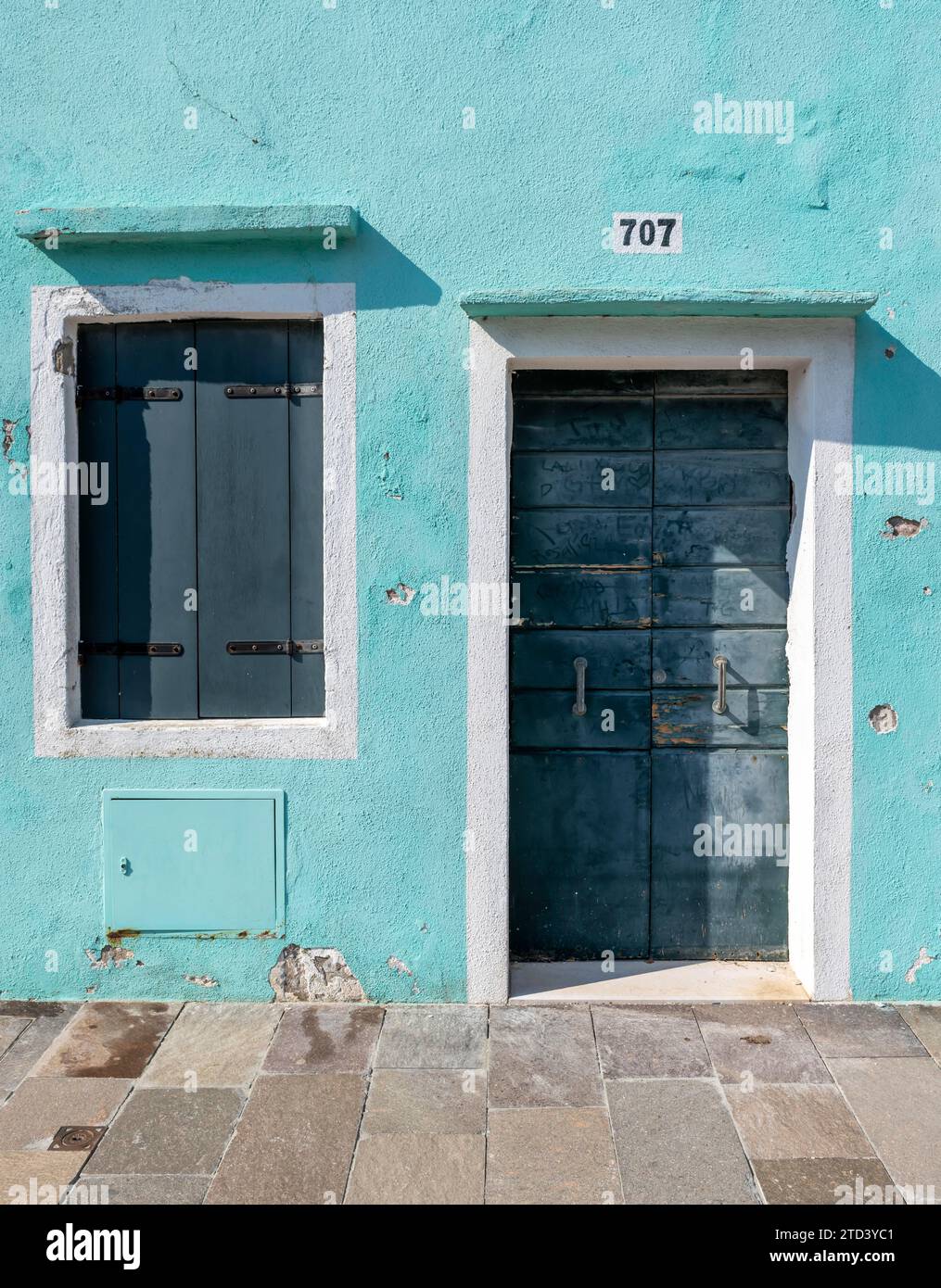 Light blue house facade with entrance door and window, colourful houses ...