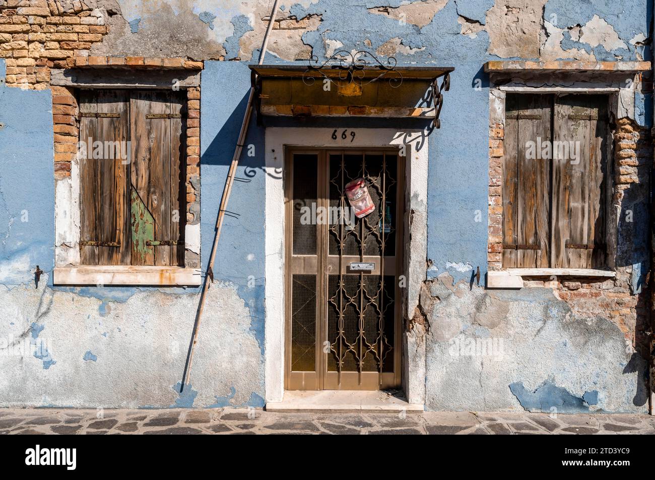 Dilapidated blue house facade with entrance door and windows, colourful ...
