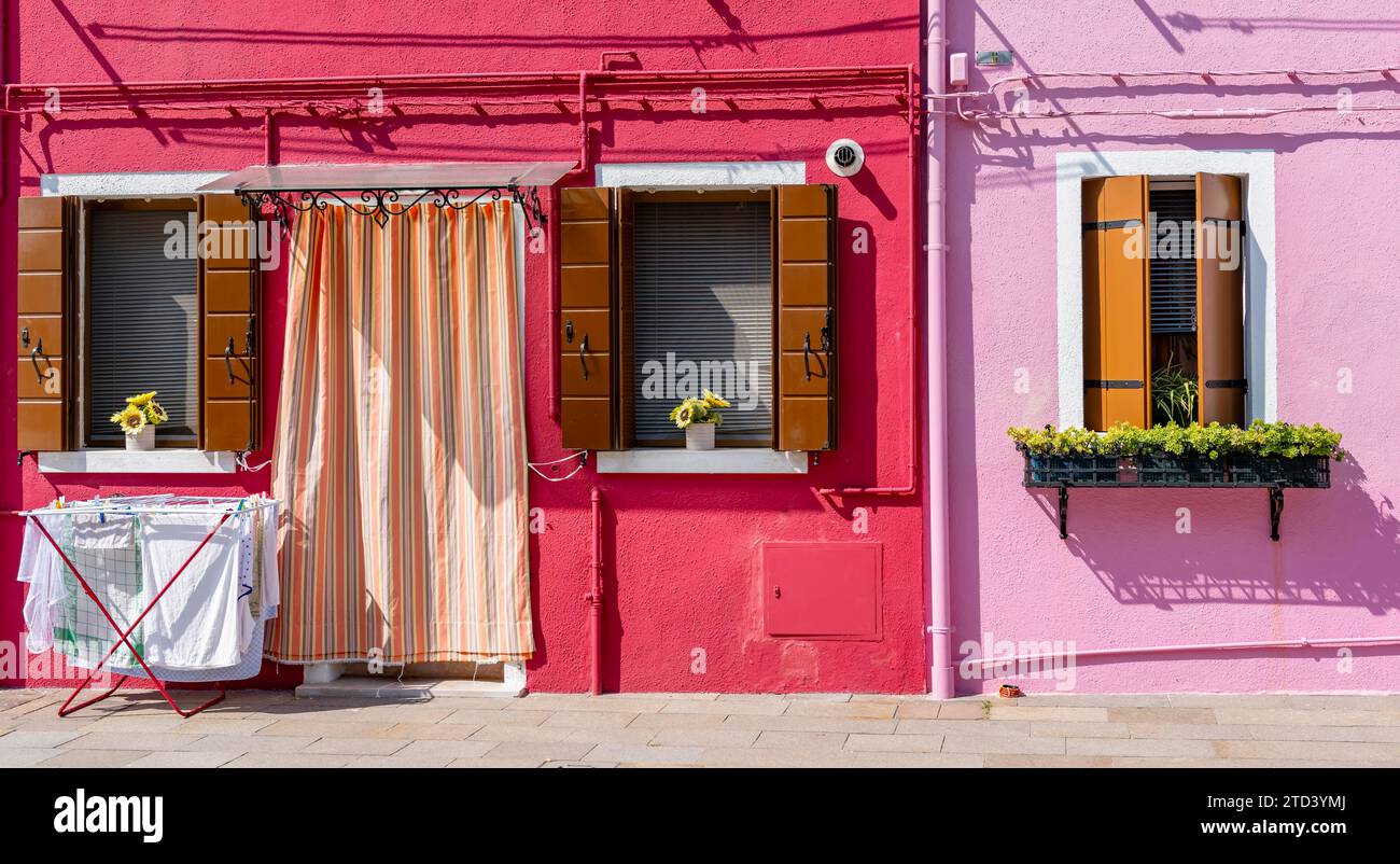 Pink and rose-coloured house facade with entrance door and windows with ...