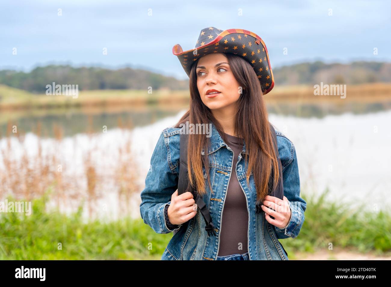Portrait of a beauty female explorer with denim clothes, bag and hat ...