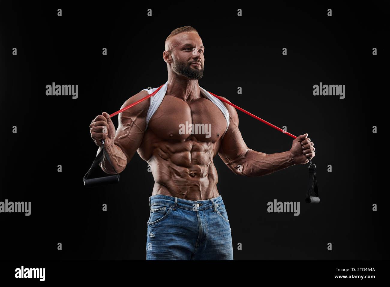 Muscular guy stretching rubber resistance bands in dark background ...