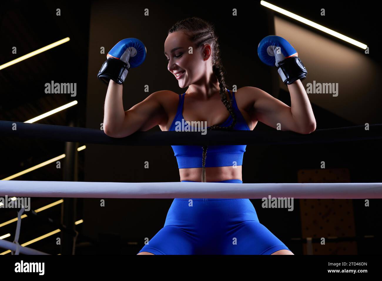 Beautiful and strong sportswoman posing on the ropes of the ring. The ...