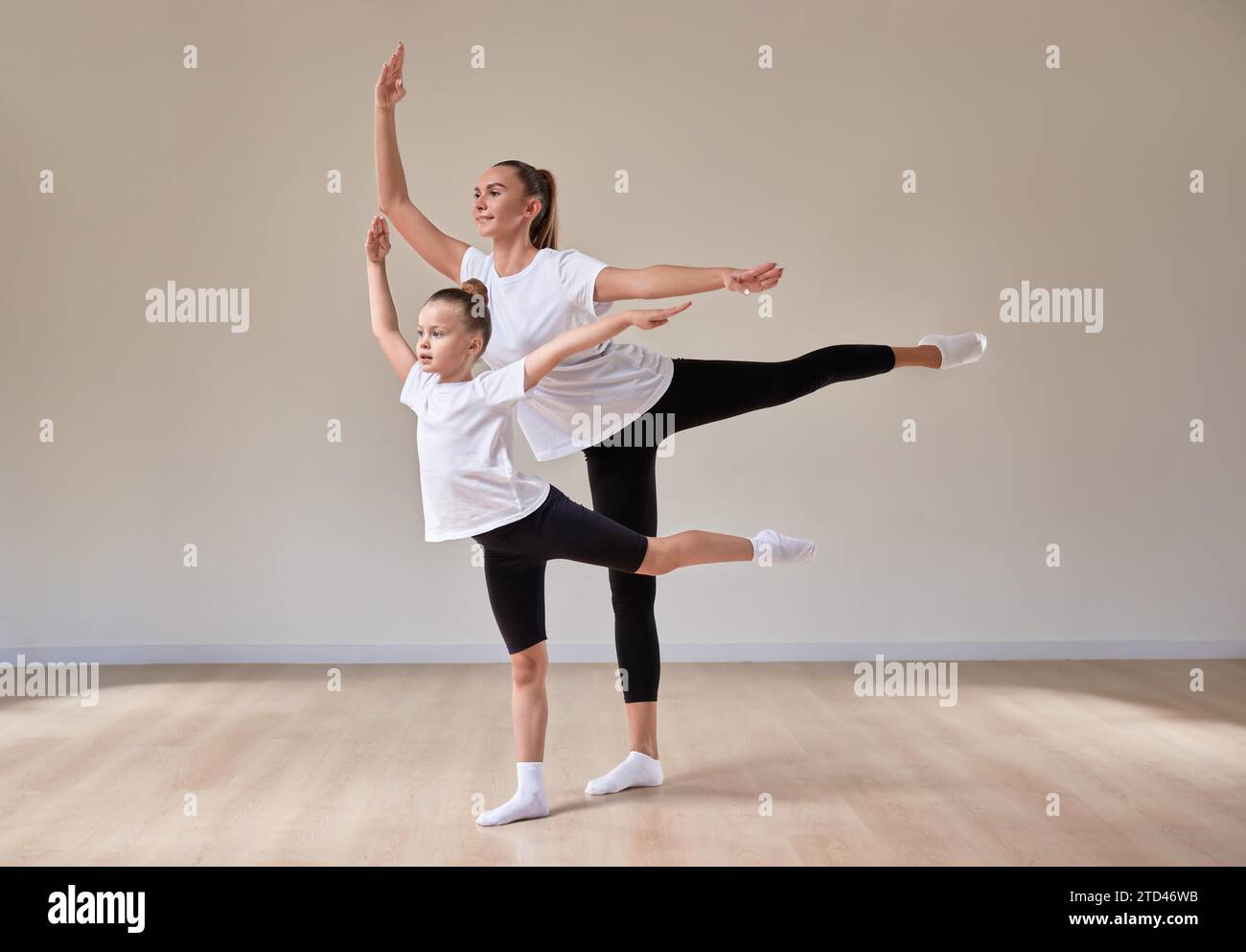 Beautiful woman teacher and a little girl perform dance movements in a ...