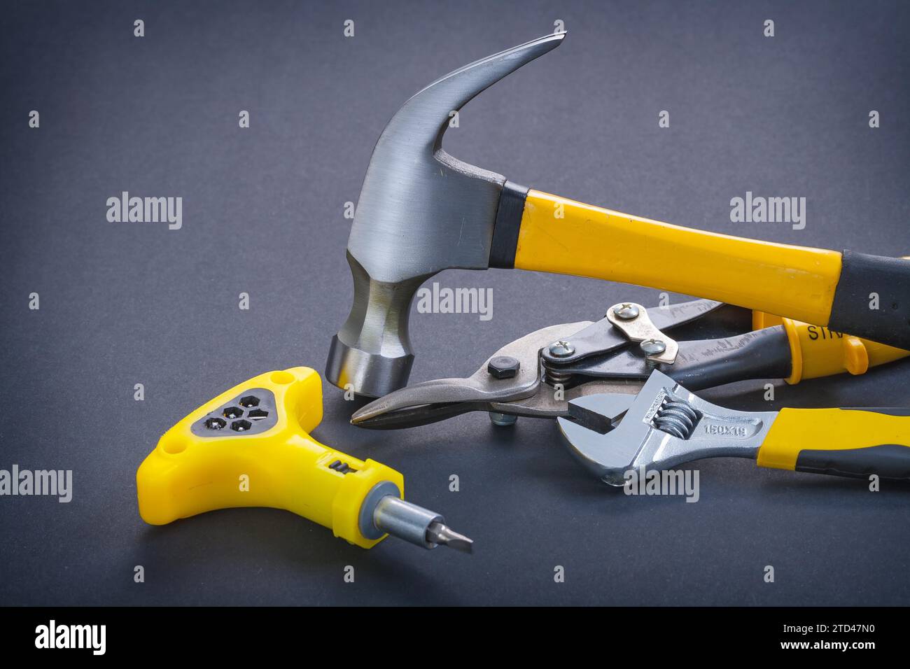 Yellow screwdriver adjustable spanner steel cutter claw hammer on black ...