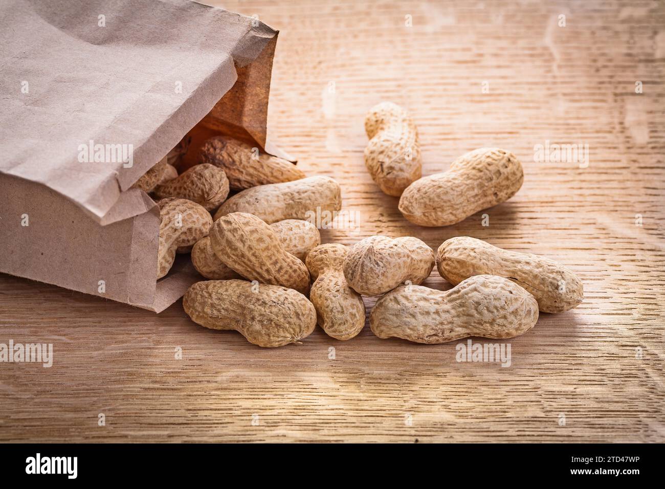 Horizontal vercion peanuts poured from paper bag on wooden board food ...
