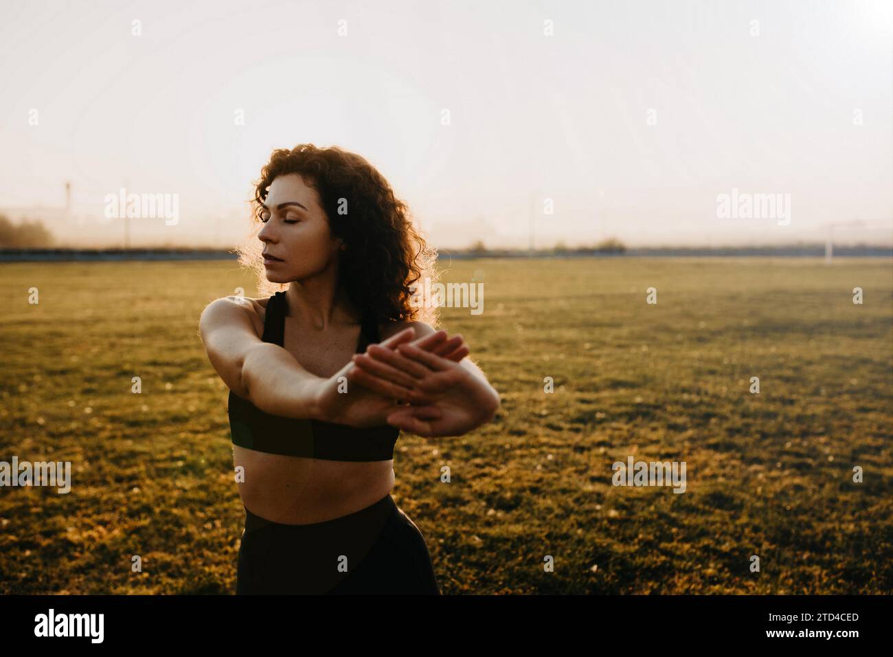 Curly girl runner doing stretching exercise on the lawn Stock Photo - Alamy