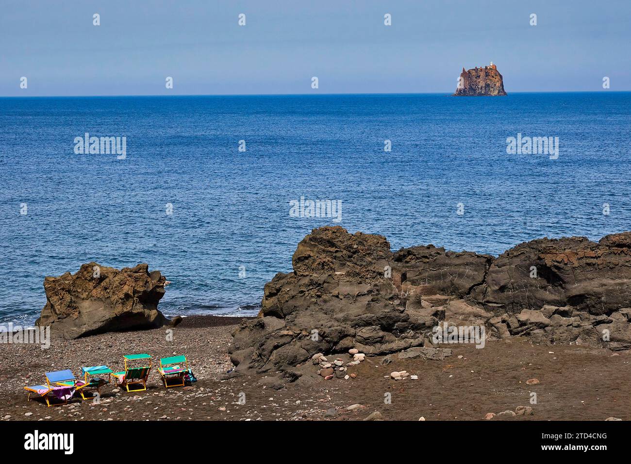 Black lava beach, deckchairs, Strombolichio, small volcanic rock island ...