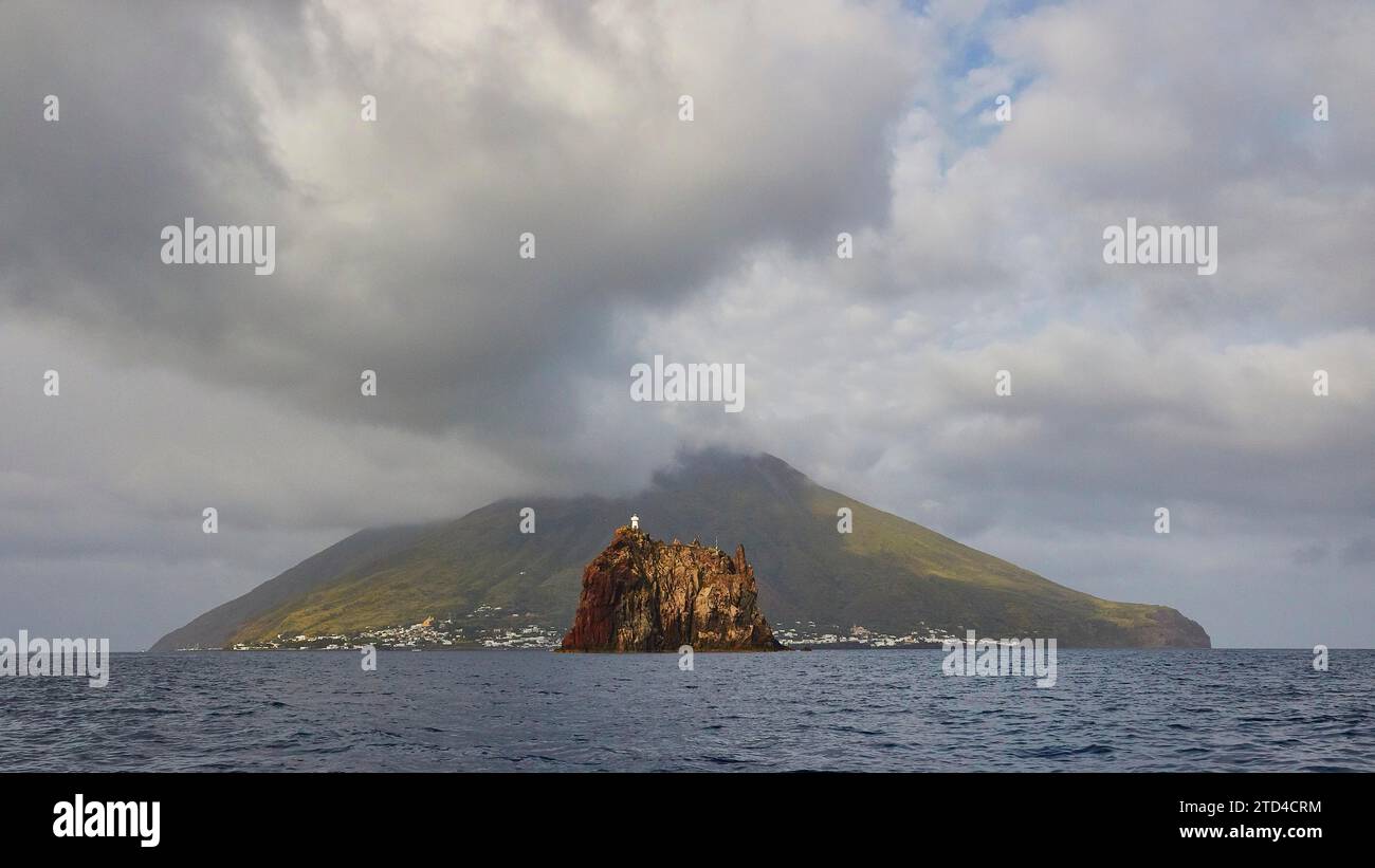 Cloudy blue sky, Strombolichio, small volcanic rock island in front of ...