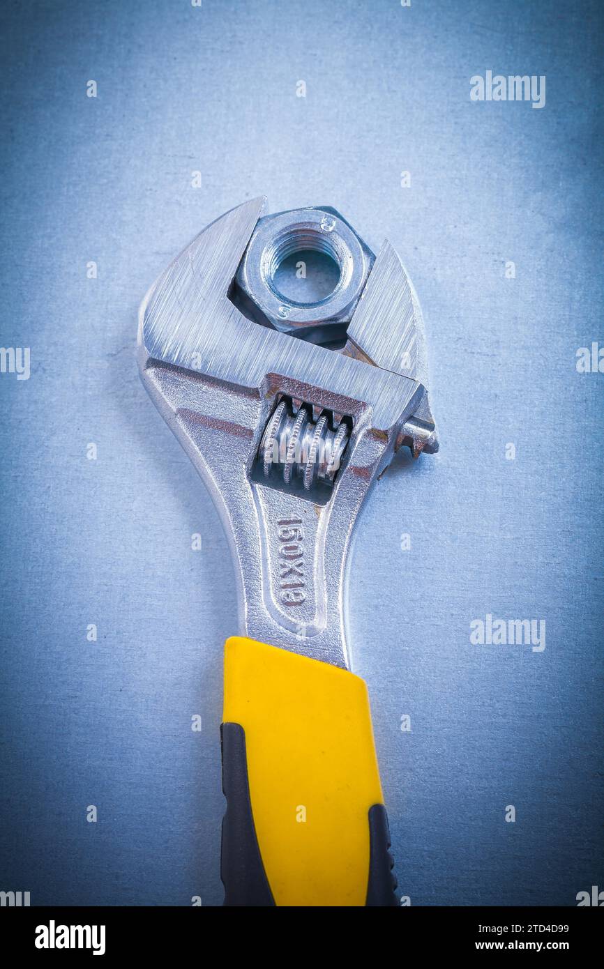 Adjustable spanner and stainless steel screw nut on a metallic ...