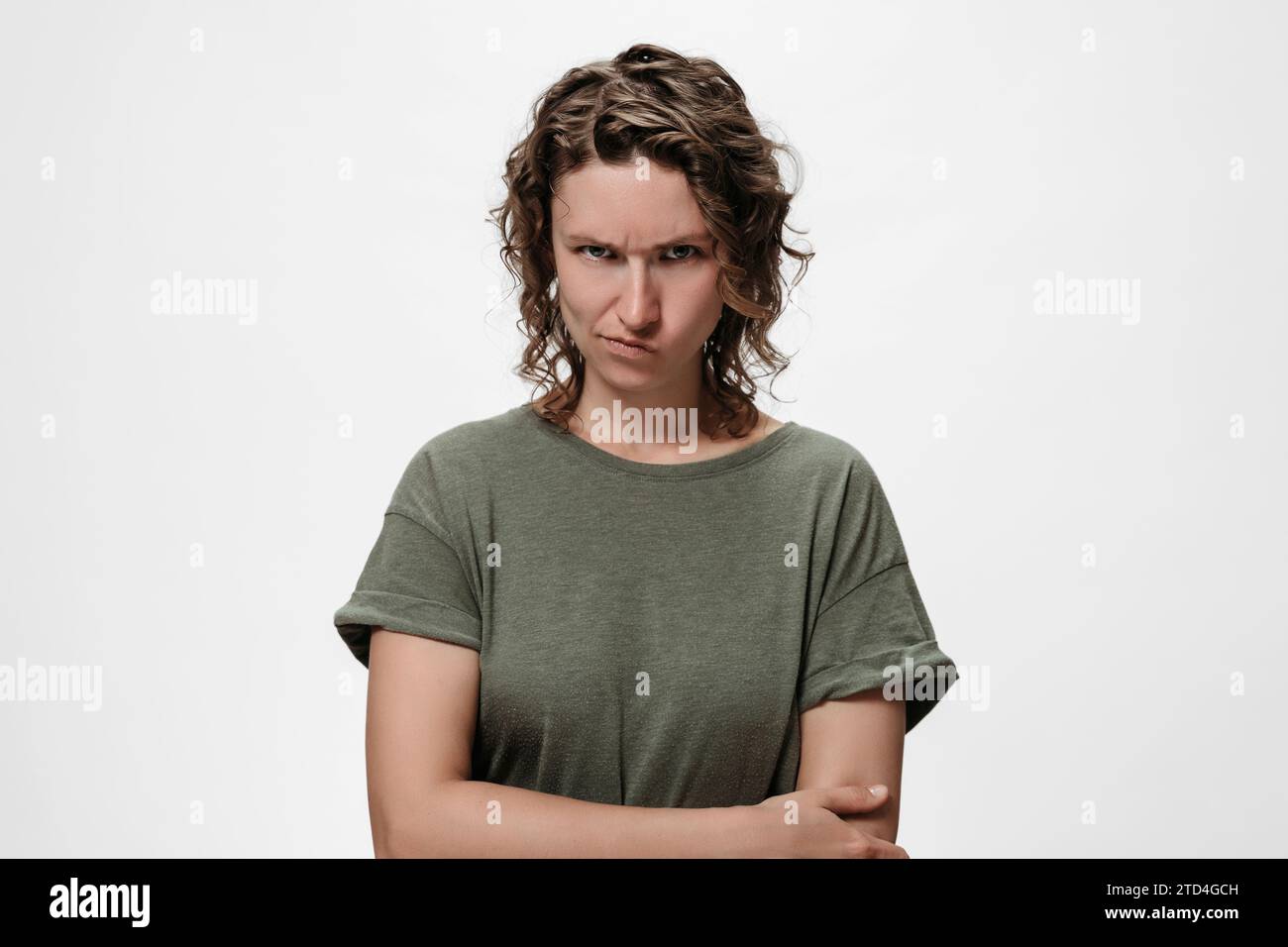 Distressed angry offended curly woman purses lips, looks with jealousy ...