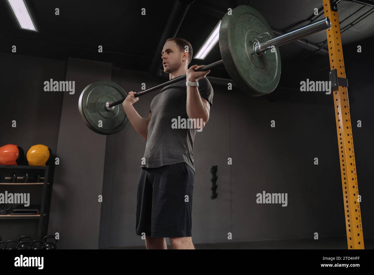 Male bodybuilder doing military press at dark gym. Weightlifter holding ...