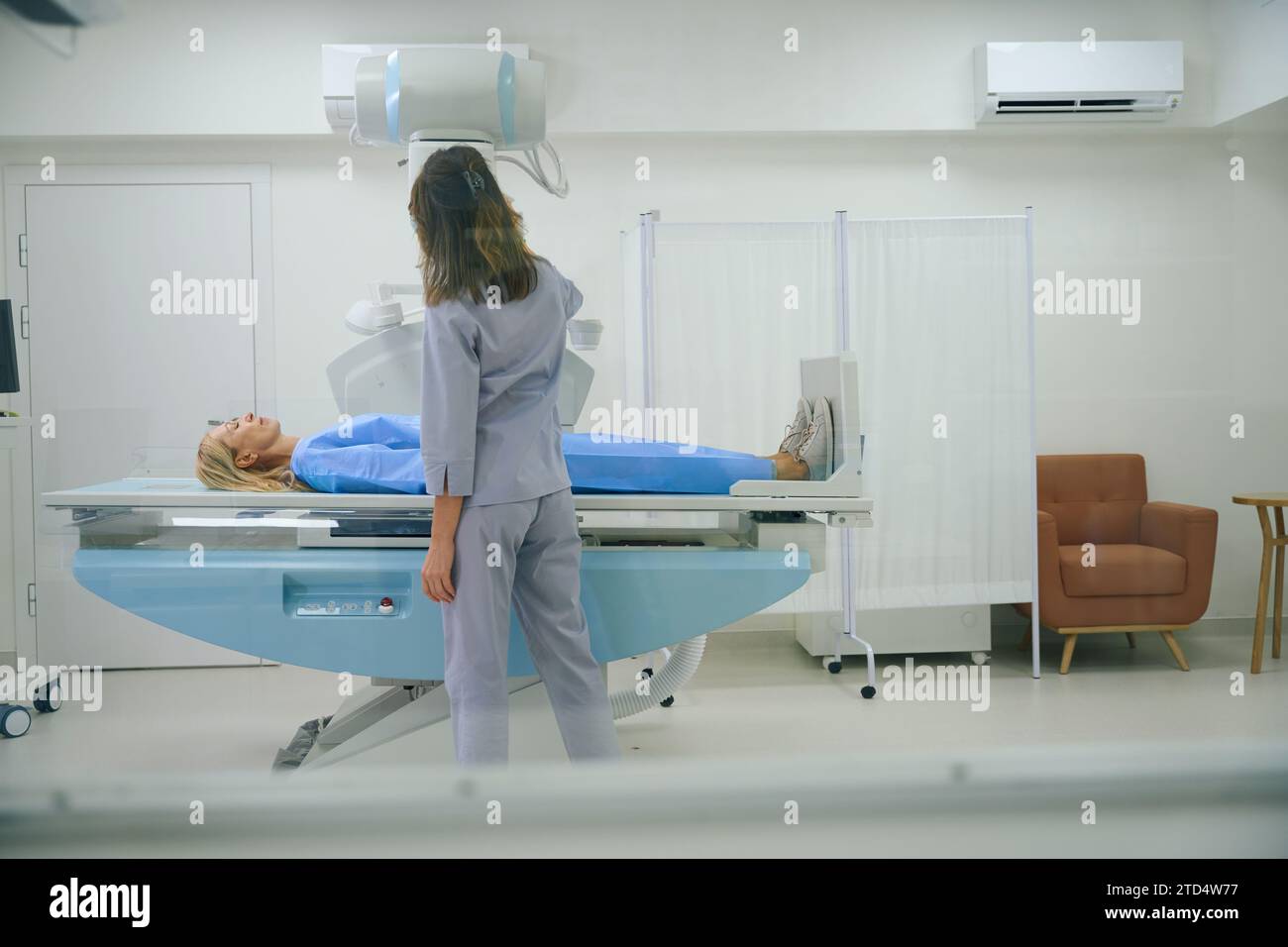 Qualified female radiographer is preparing patient for diagnostic ...