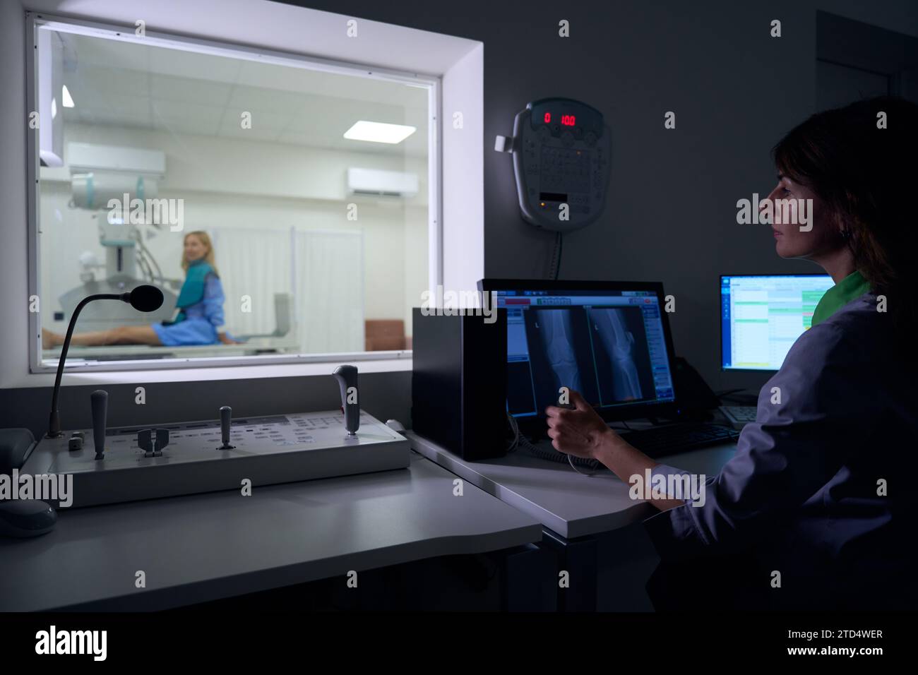 Qualified radiographer performing digital knee radiography on adult ...