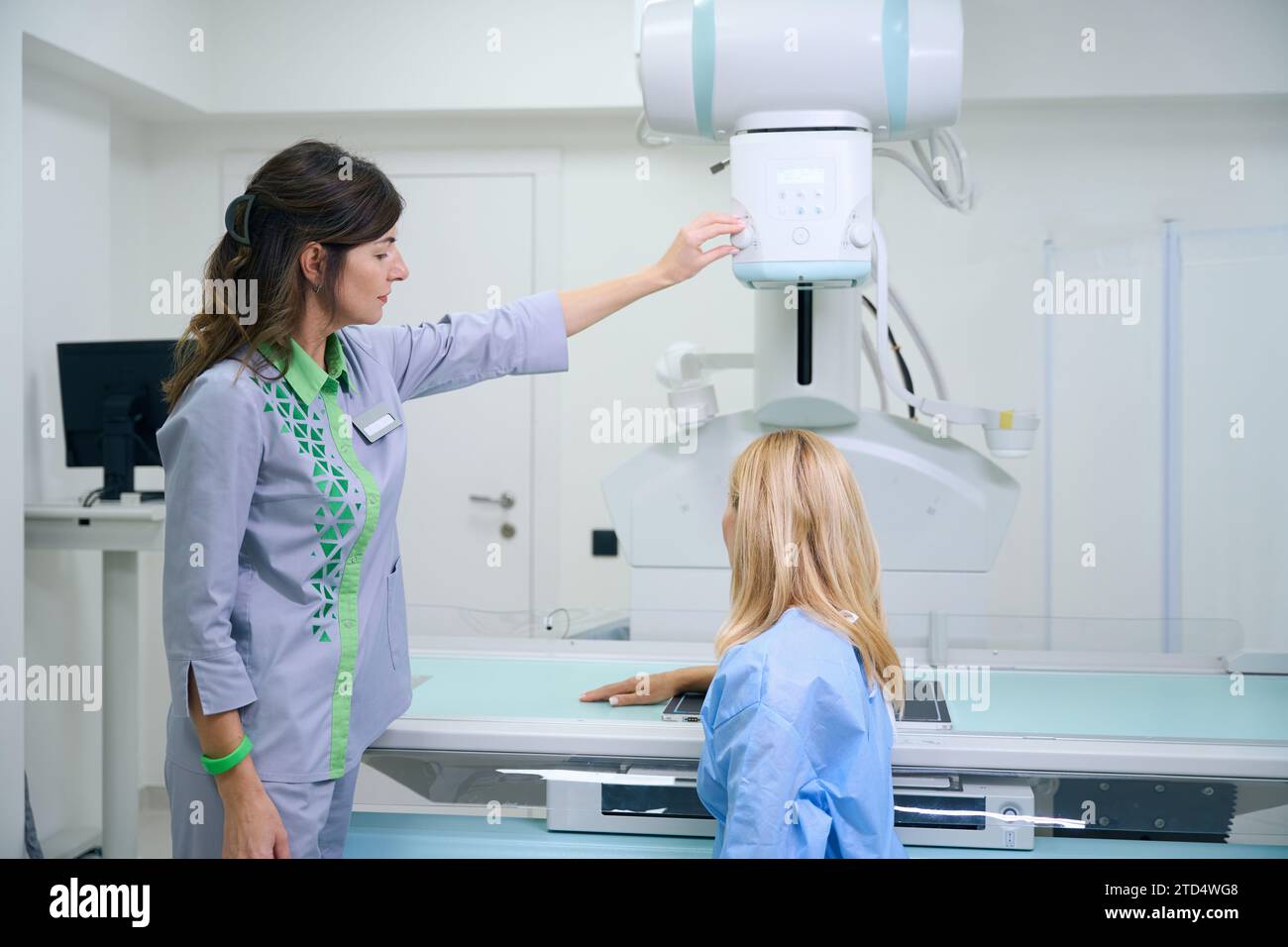 Radiologic technologist preparing adult female for upper extremity radiography Stock Photo - Alamy