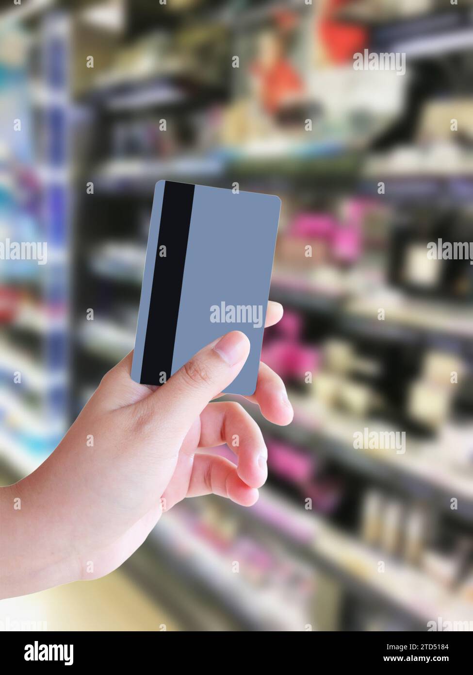 Female hand holding credit card with beauty and cosmetics shelves in ...