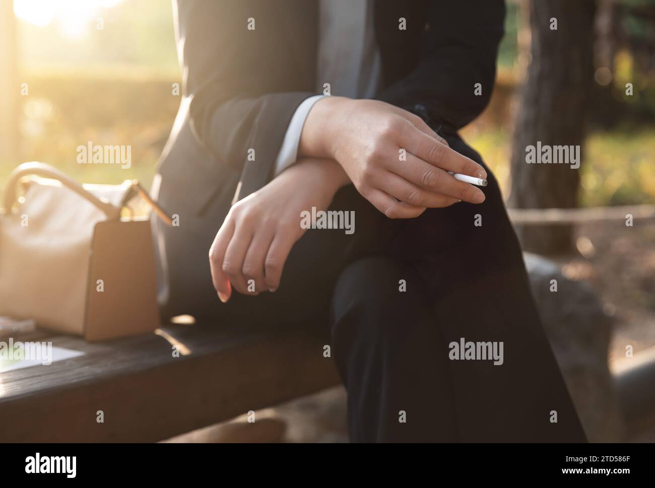 A woman is sitting on a park bench and smoking a cigarette Stock Photo ...