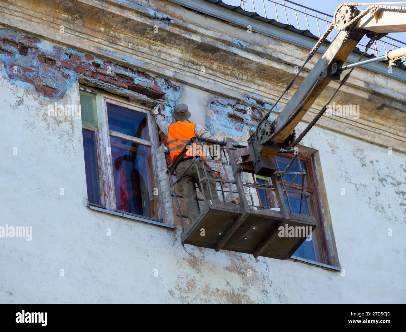 A worker repairs the facade of an old building Stock Photo - Alamy