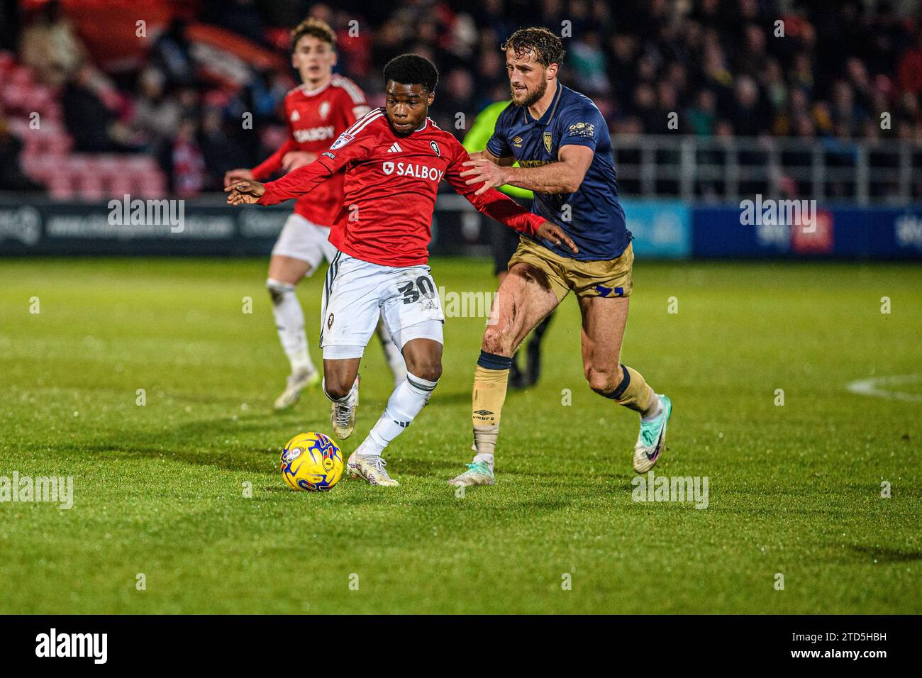 Salford, UK. 16th December 2023.Wimbledon's Joe Lewis pulls the arm of ...