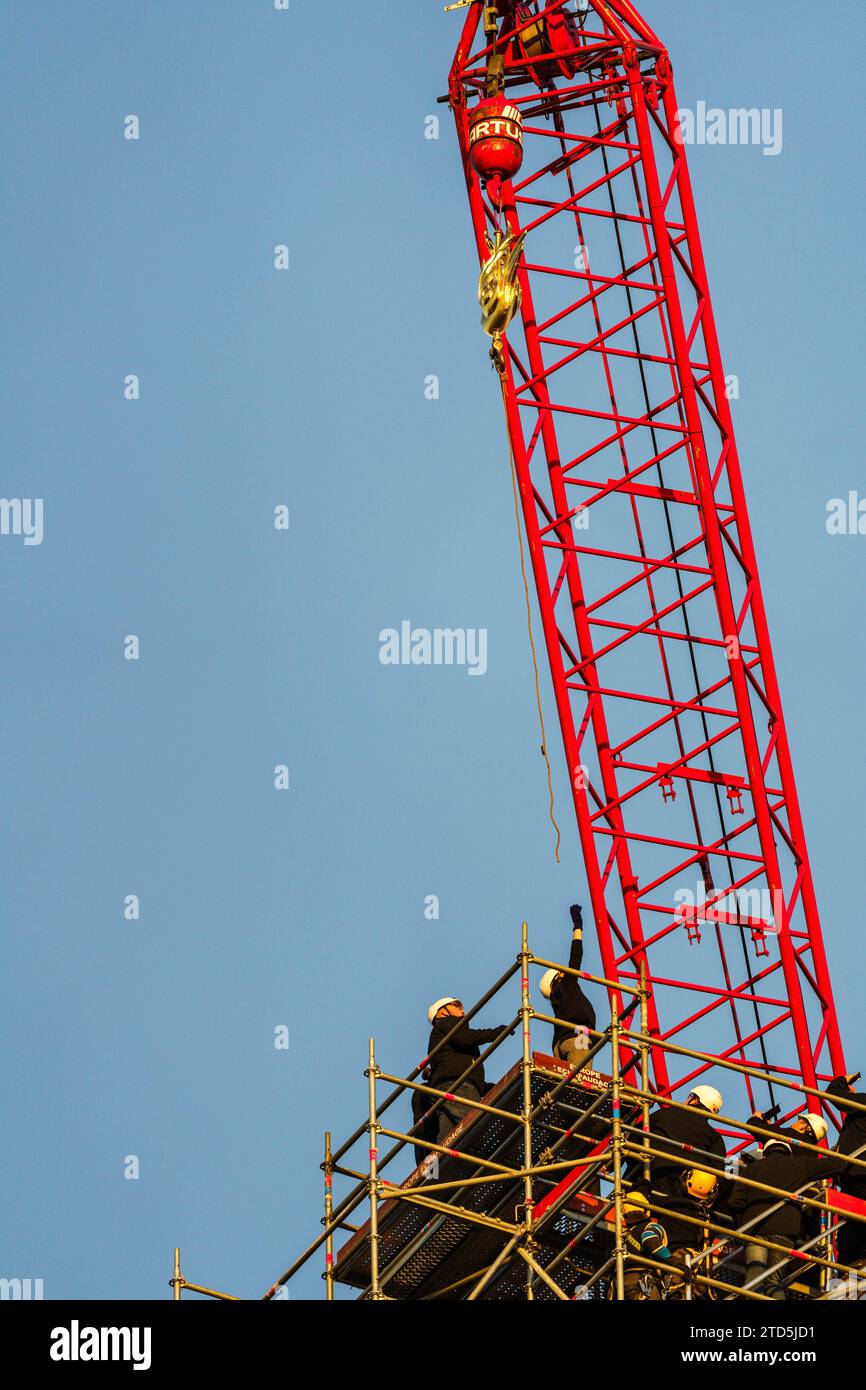 The new golden rooster containing relics is lifted by crane to be ...